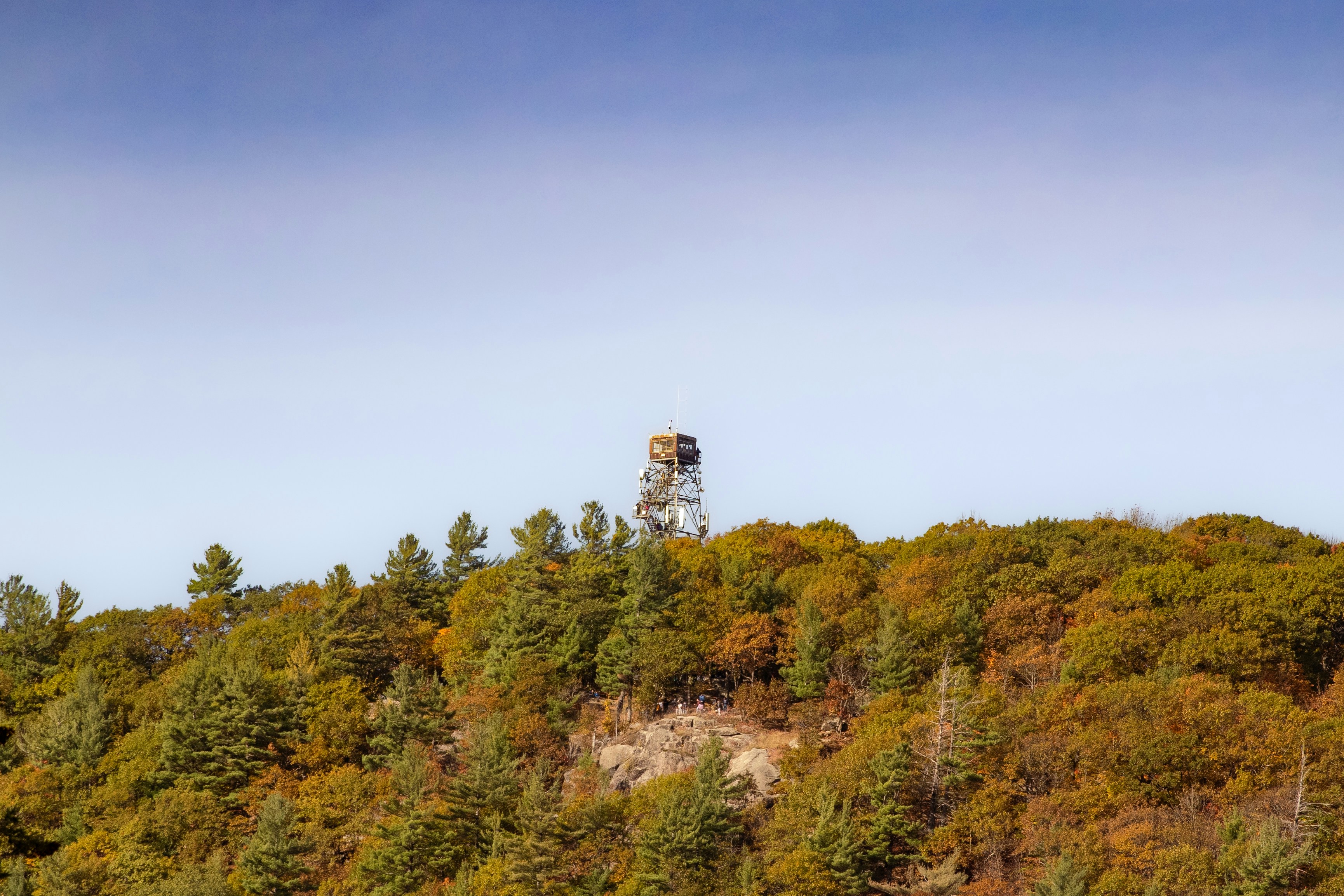 A lookout tower atop a hill surrounded by colorful autumn trees.