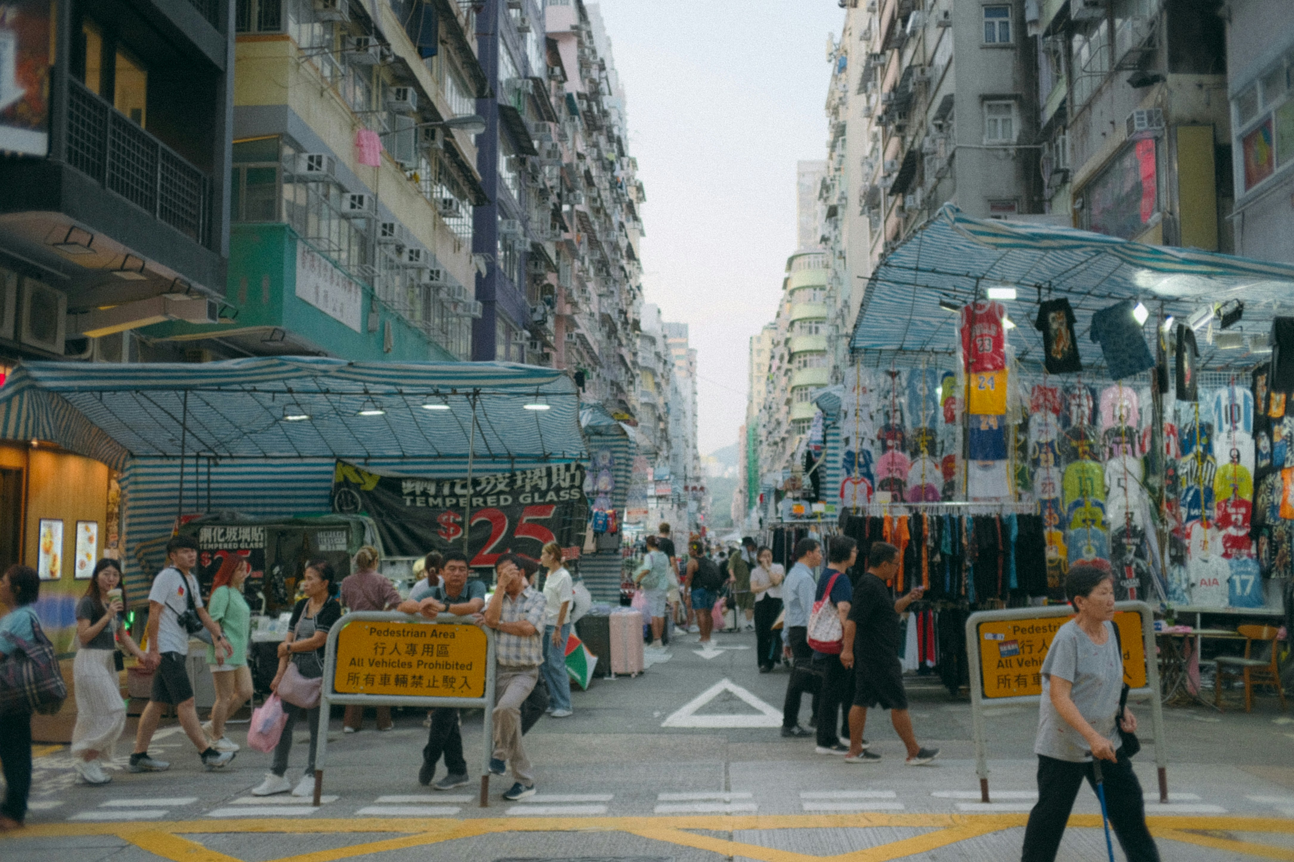 A crowd of people walking down a street next to tall buildings photo ...