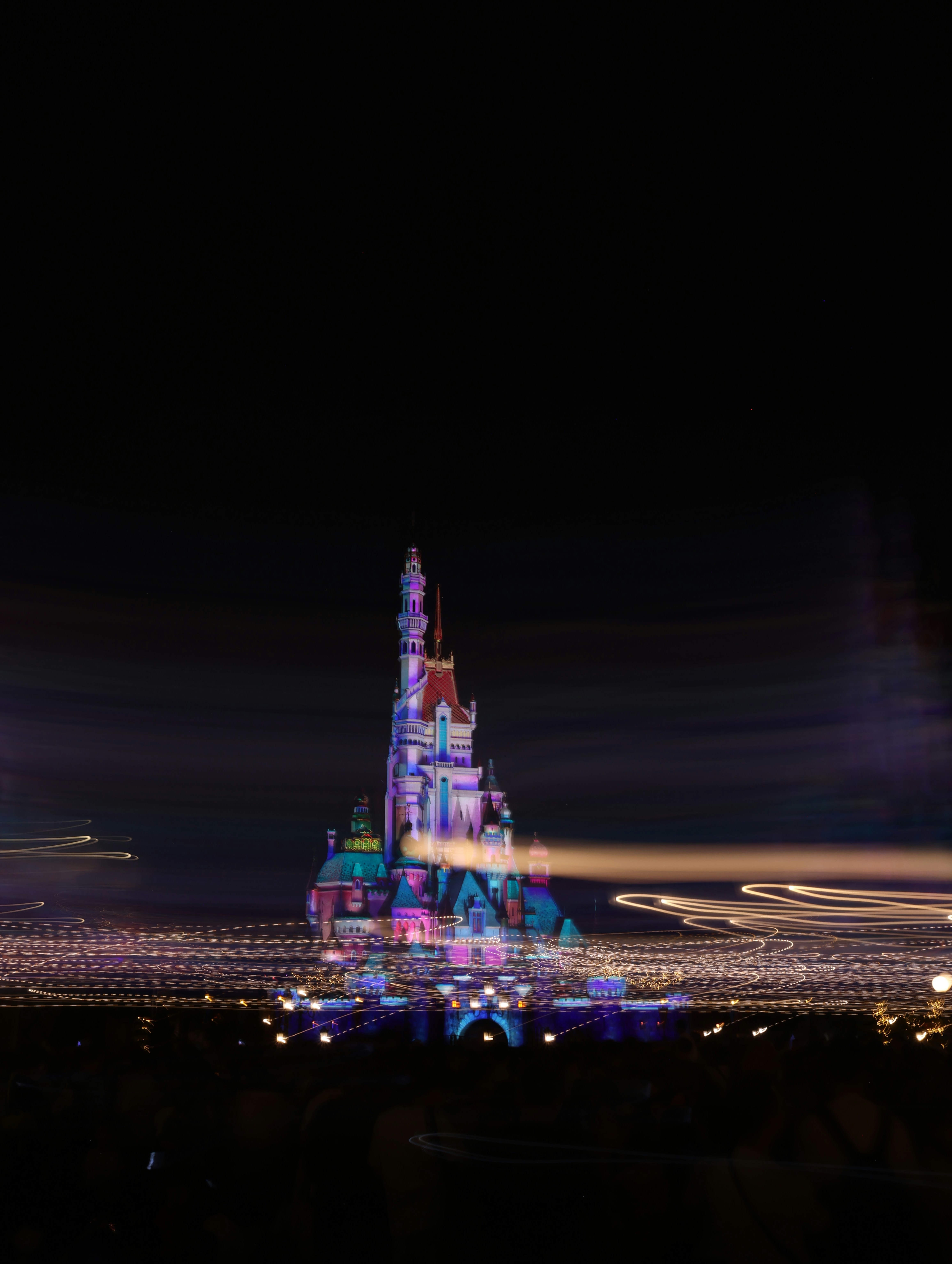 Vibrantly illuminated castle amidst swirling lights at night, showcasing a magical atmosphere. The scene captures the essence of a festive celebration.