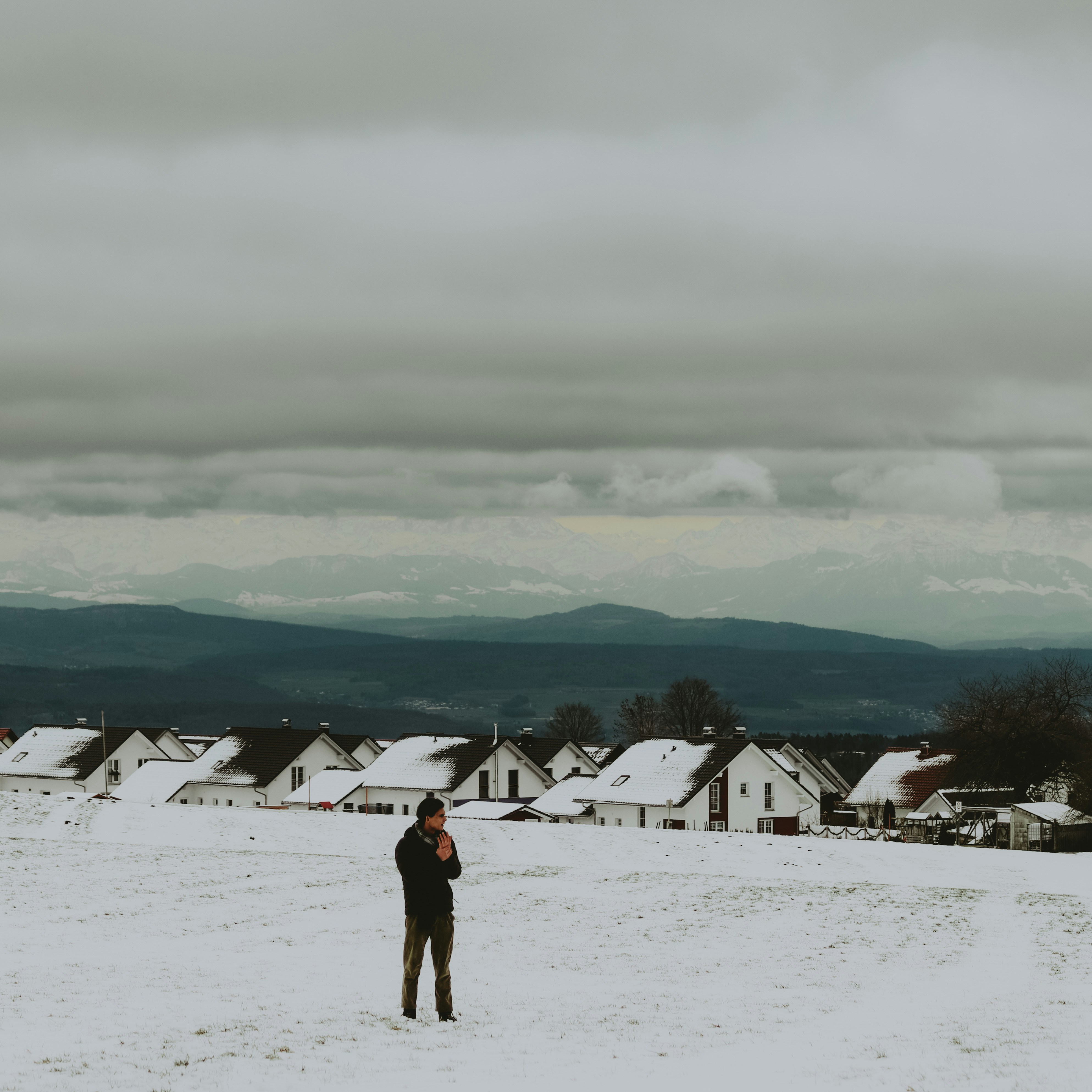  lone figure in a snowfield beneath layered clouds