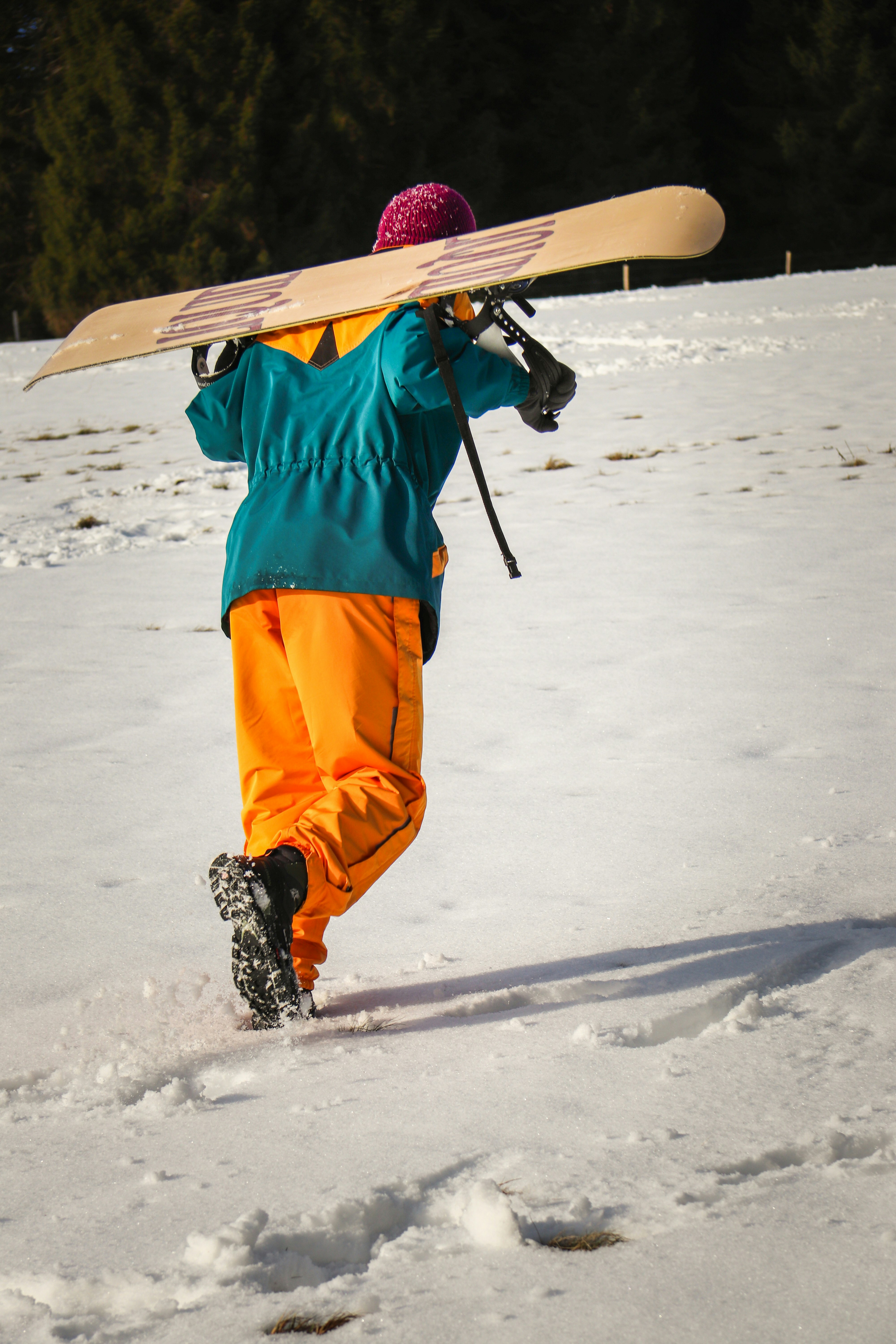 A person walking in the snow with a snowboard on their head photo ...