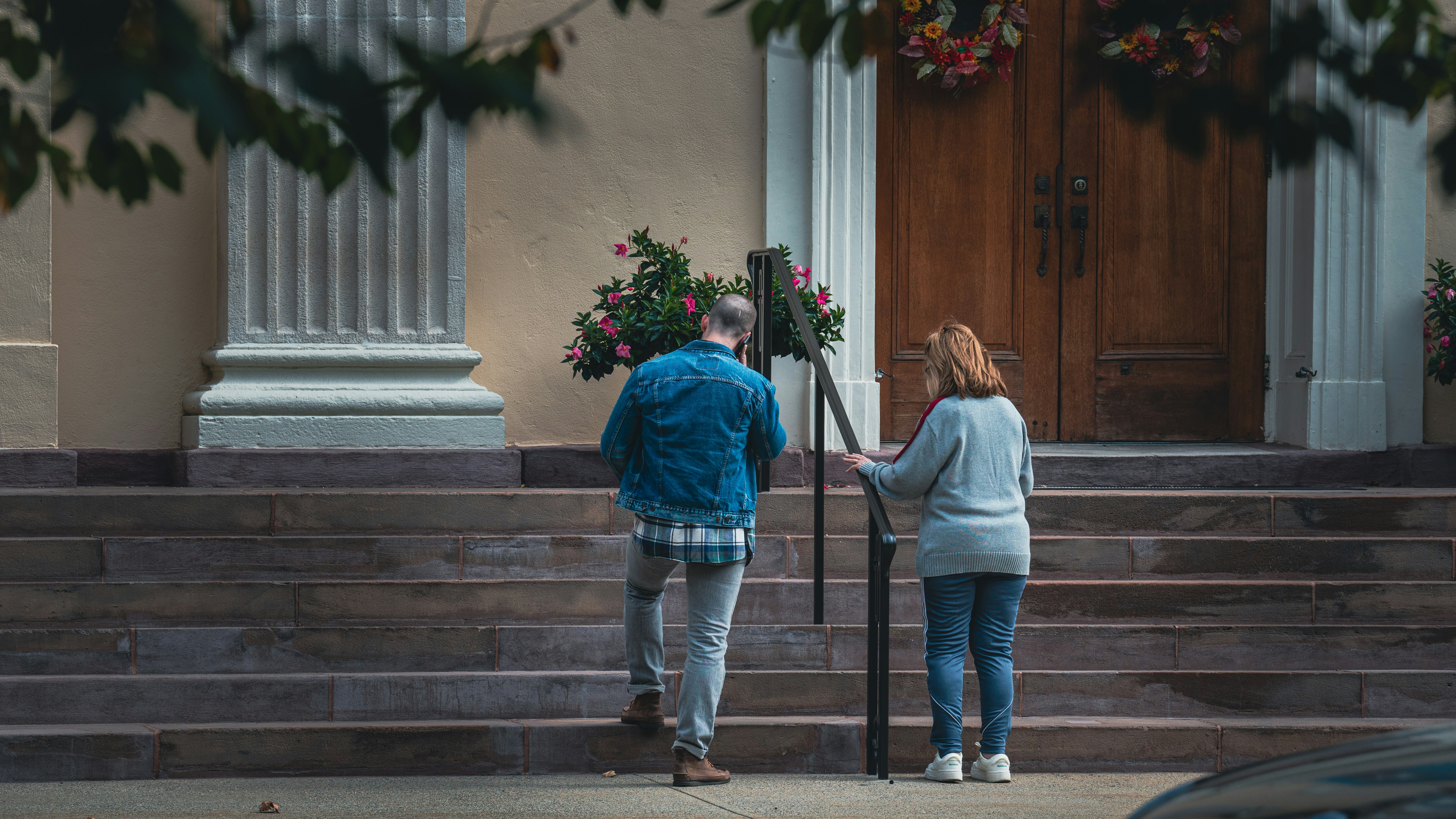 Threshold Dialogue: Denim-Clad Duo on a Sunlit Staircase