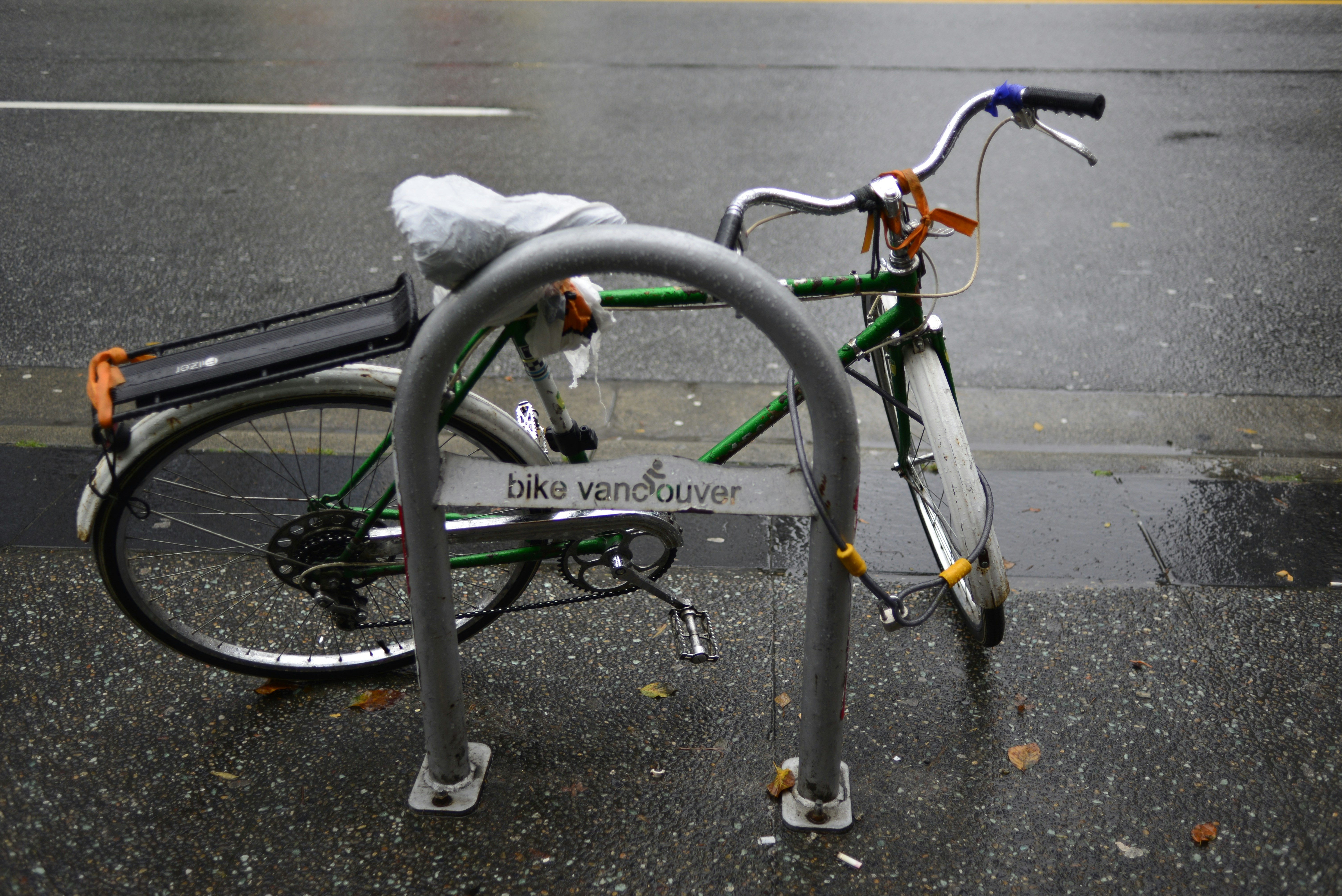 Green Bicycle Locked to a Rain-Slick Vancouver Street Rack