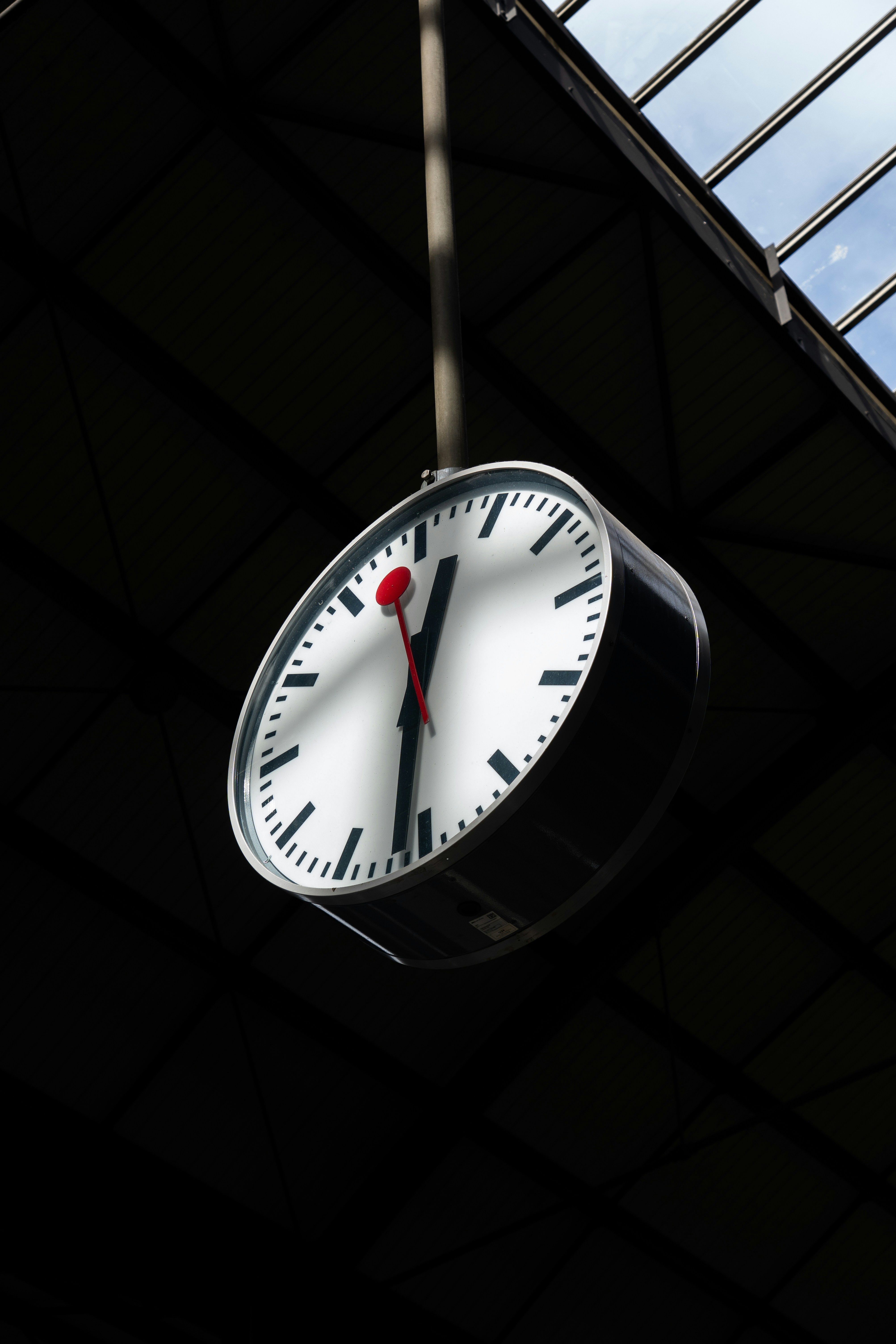 A clock hanging from the ceiling of a train station