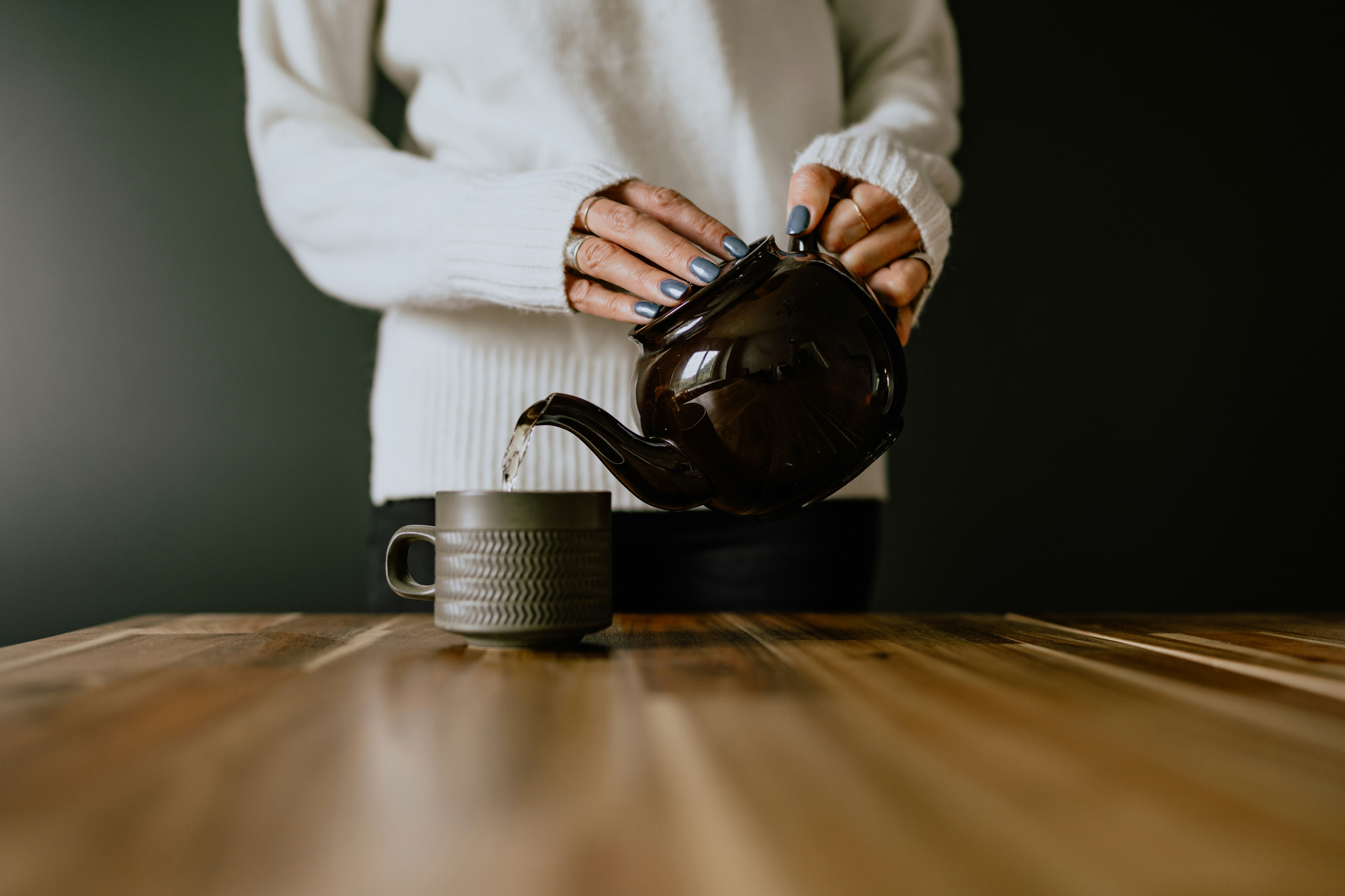 A person holding a teapot on a wooden table photo – Free Wood Image on ...