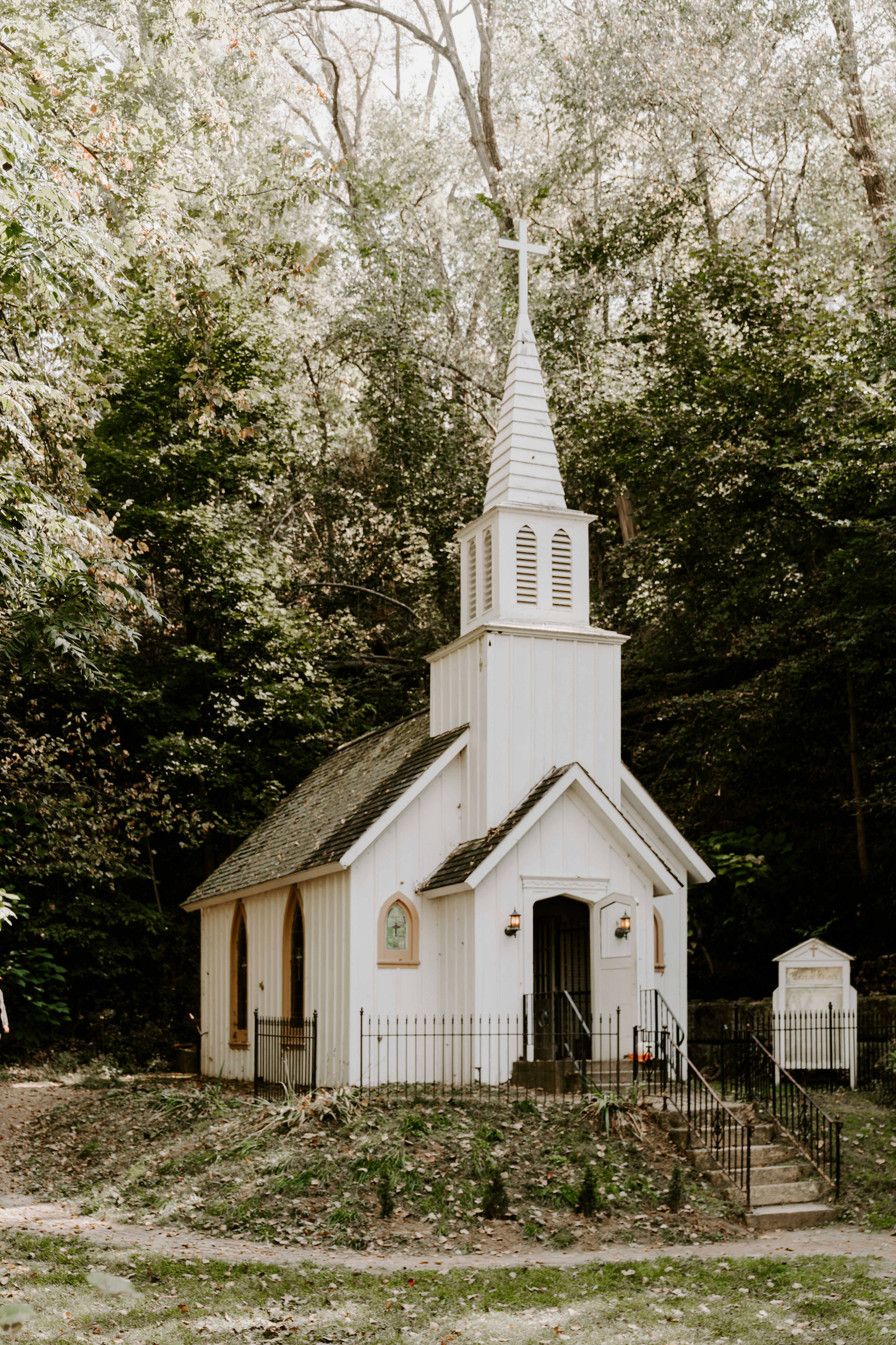 White chapel nestled in a lush forest clearing under soft daylight.