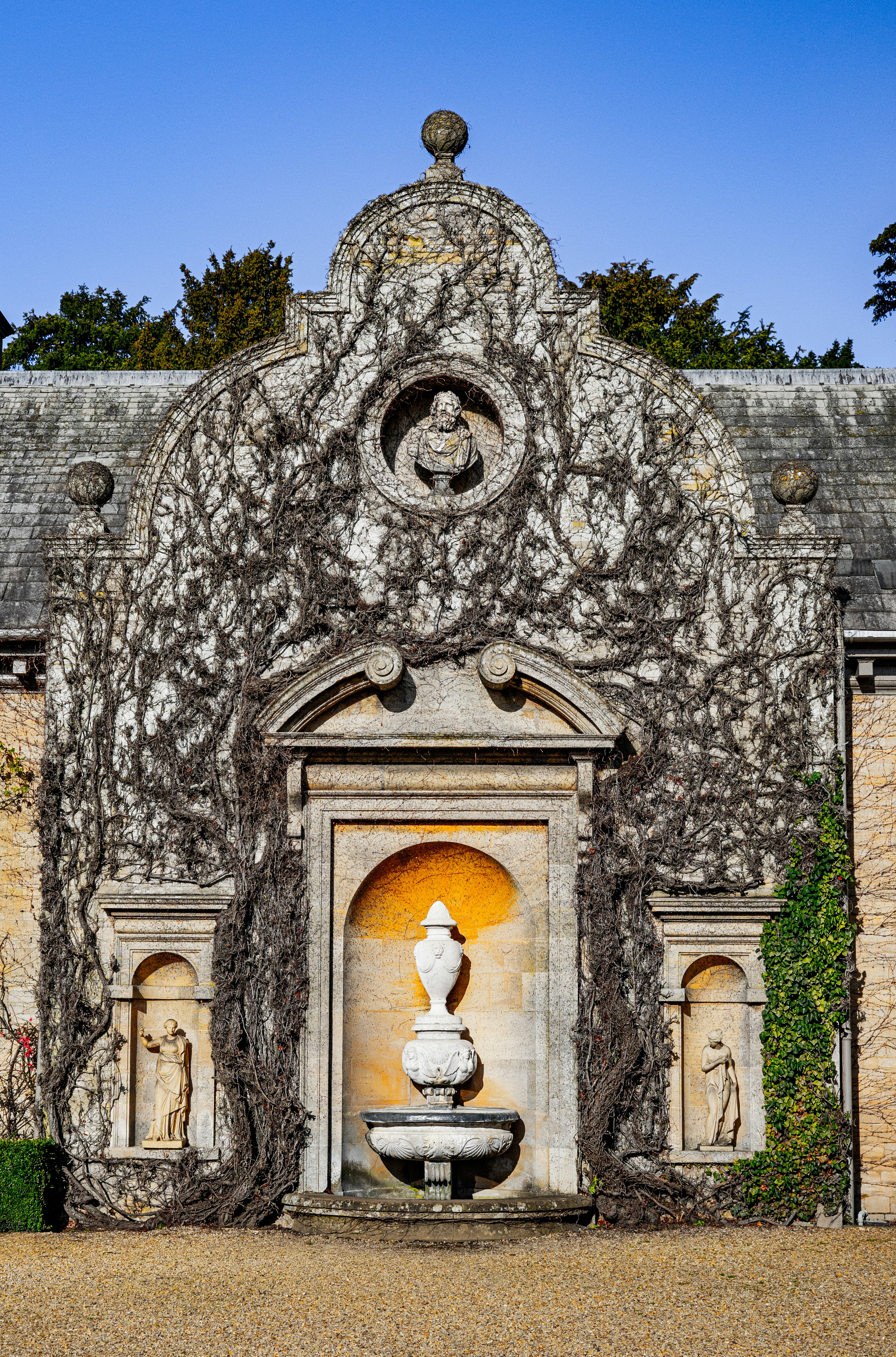 Sunlit Urn Fountain Framed by an Ivy-Covered Classical Facade