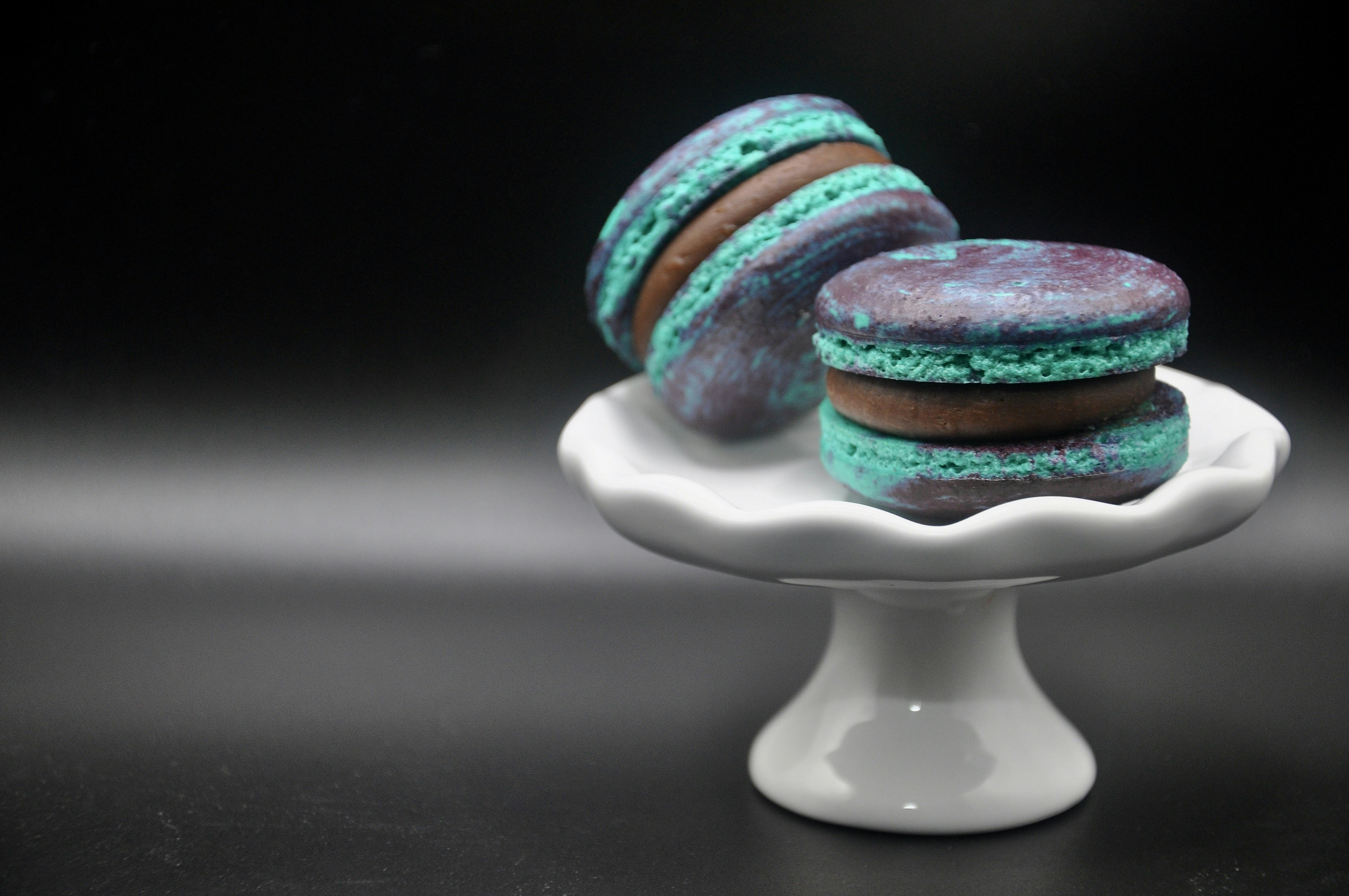 Teal and Plum Macarons on a White Pedestal: A Studio Still-Life Study