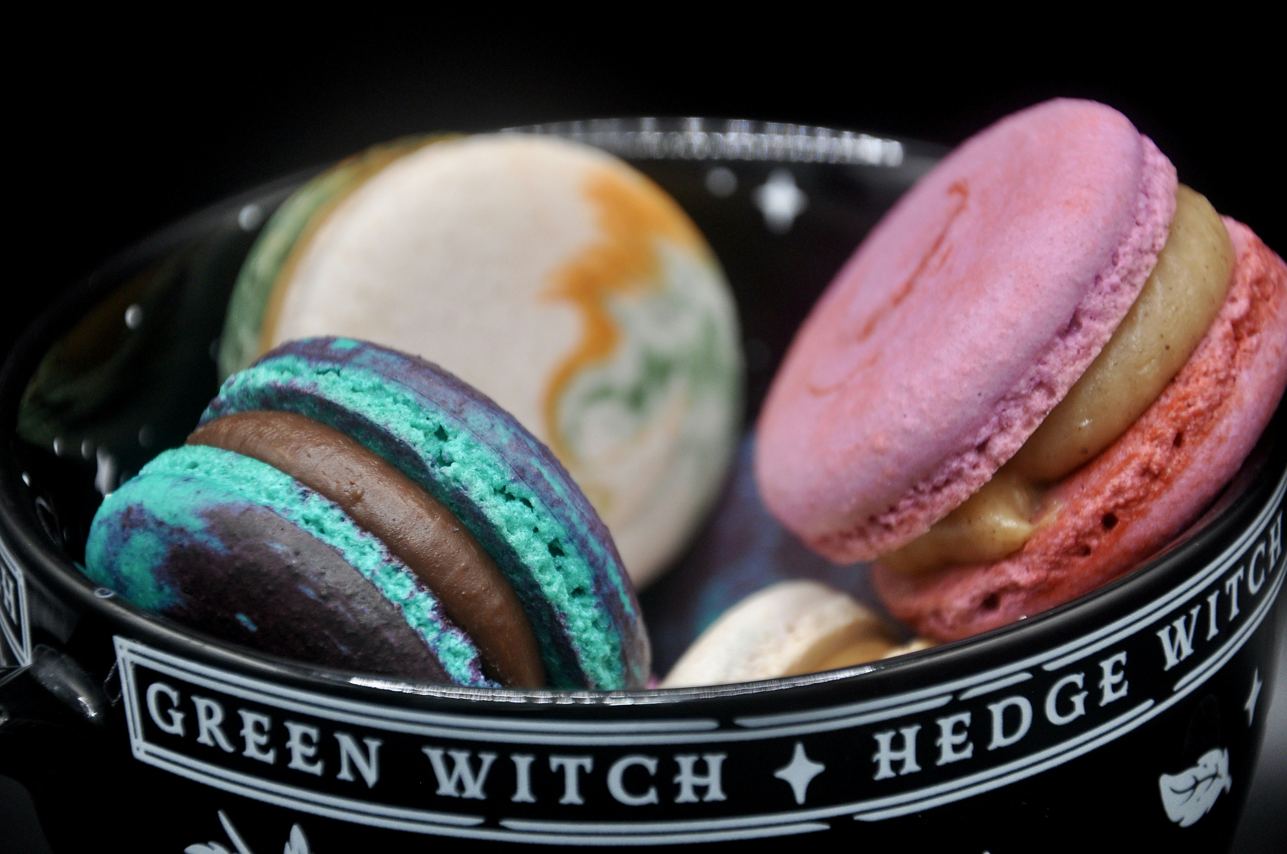 A bowl filled with different colored macaroons on top of a table photo ...