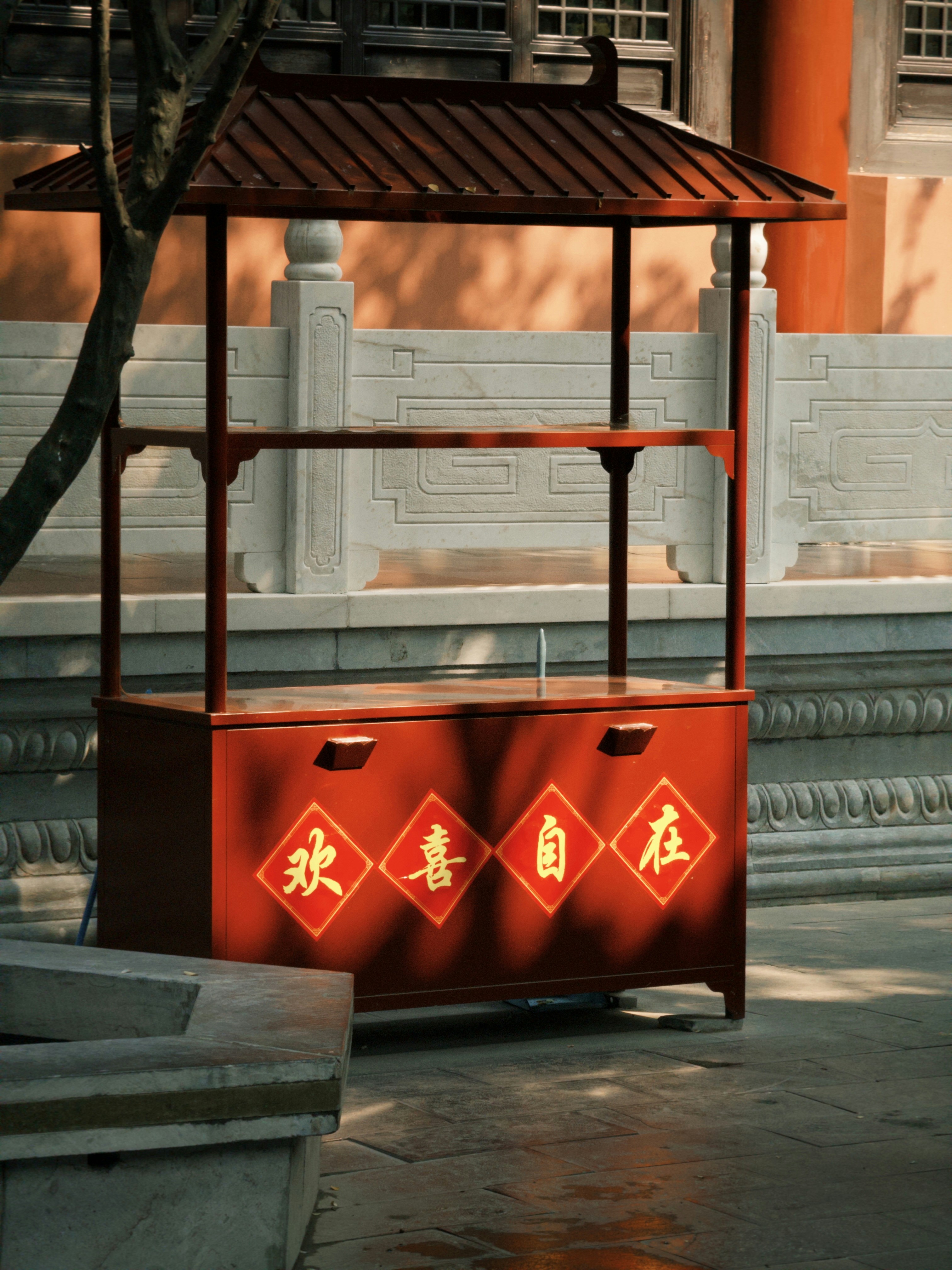Diamond-Emblazoned Red Cabinet in a Sunlit Temple Courtyard