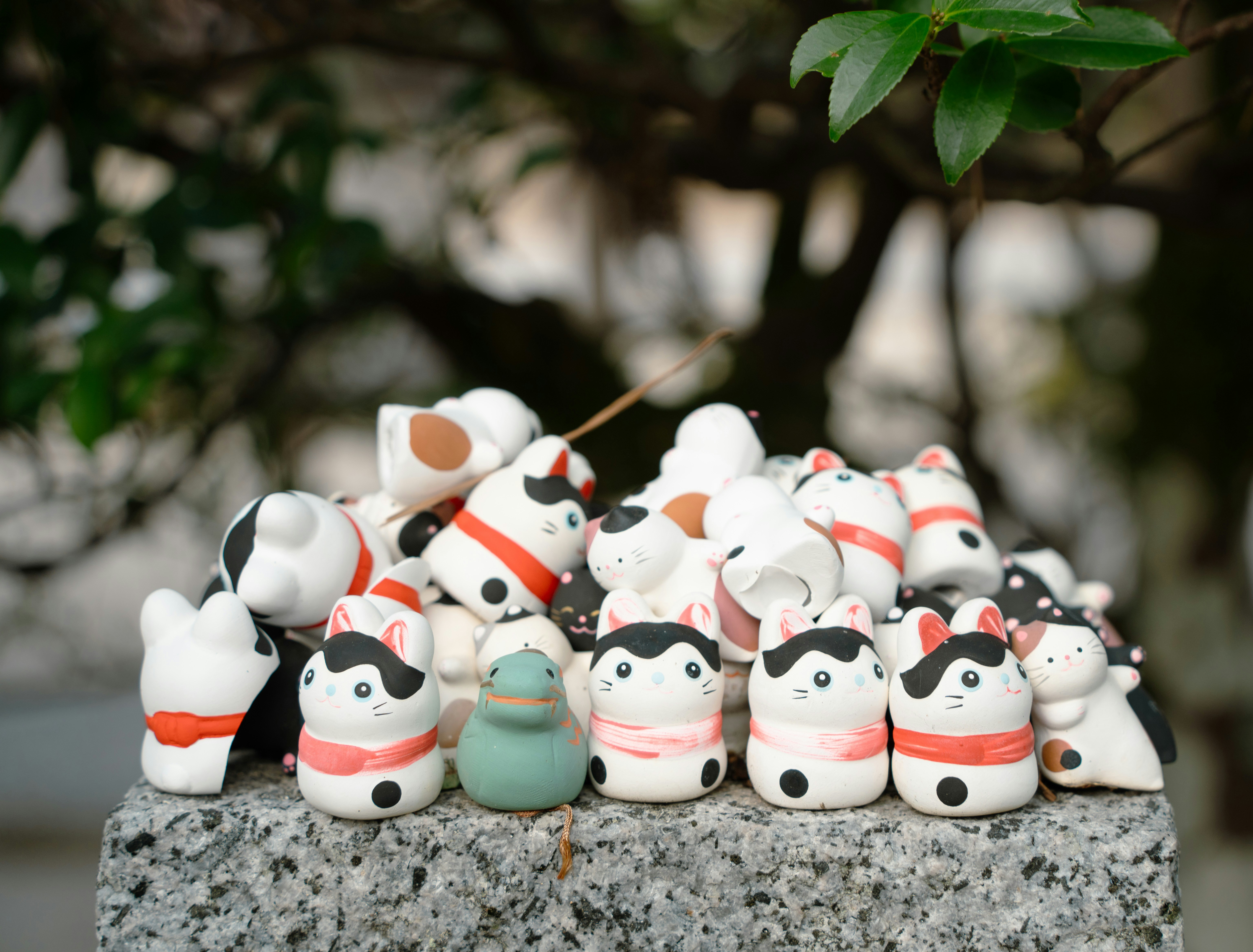 Row of Tiny Ceramic Cat Figurines Guarding a Stone Altar