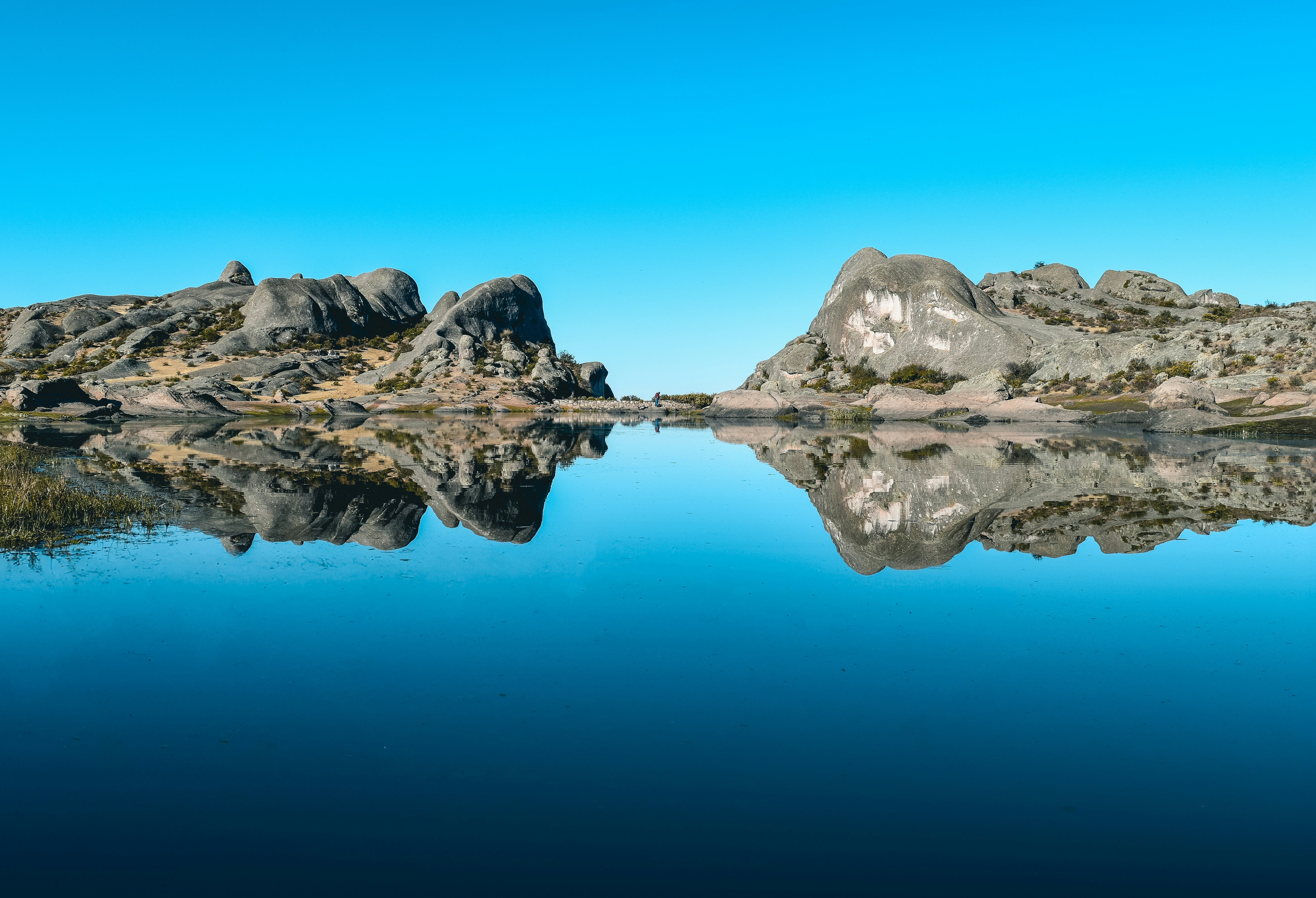 A body of water surrounded by rocks and a blue sky photo – Free Lima ...