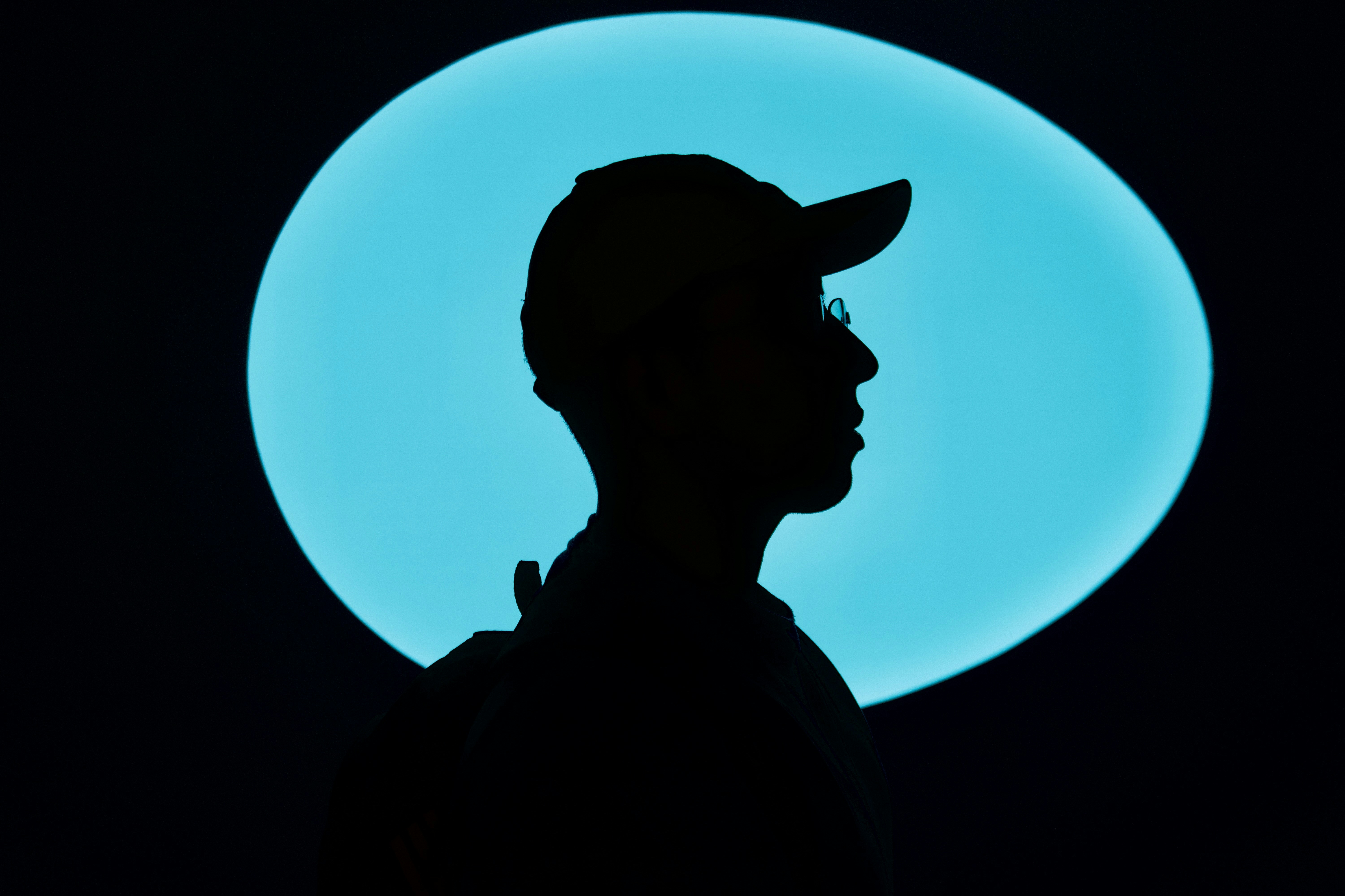 Haloed Silhouette: A Quiet Profile Before a Cyan Orb