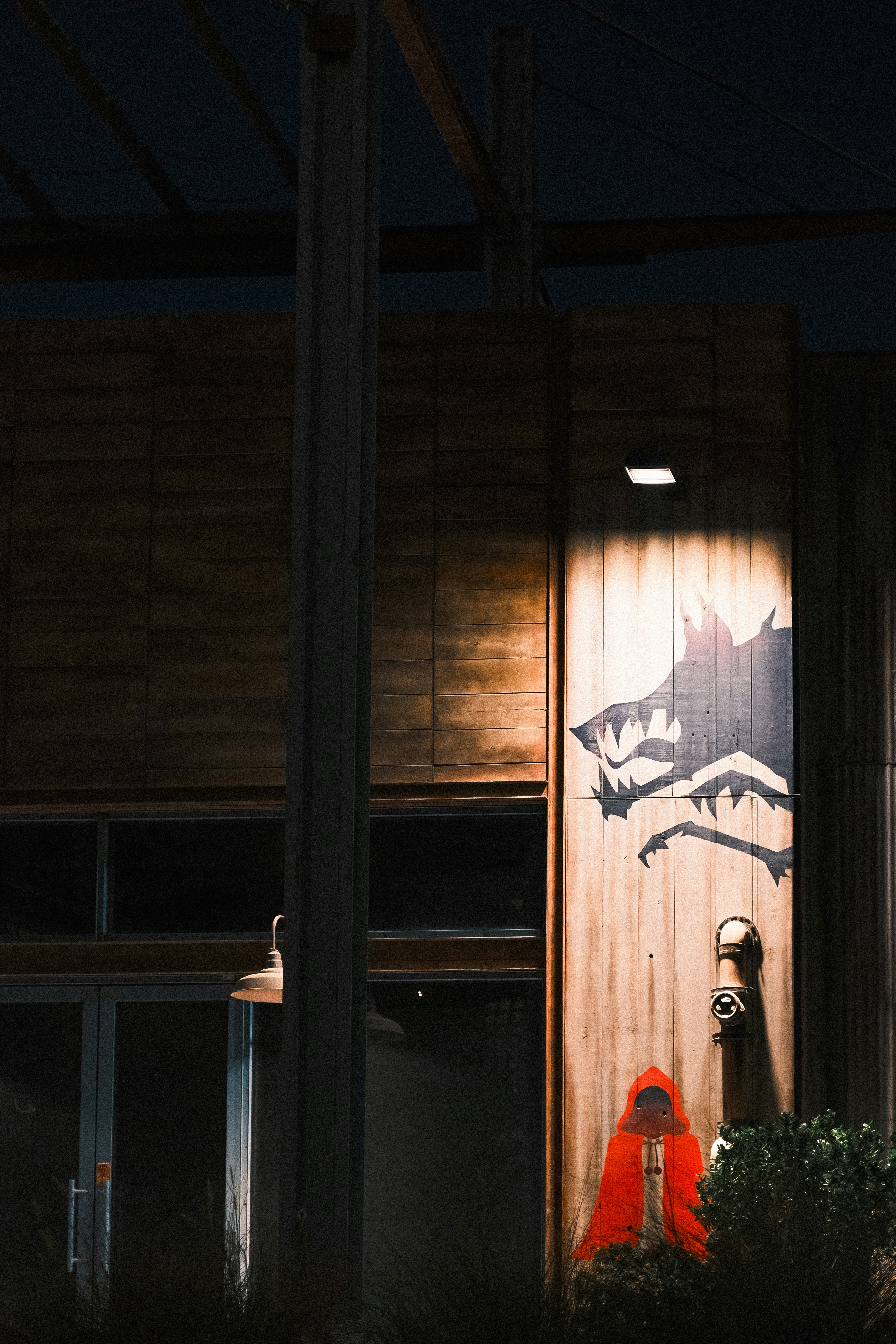 Crimson Cloak on a Wood-Walled Facade Beneath a Shark-Mural