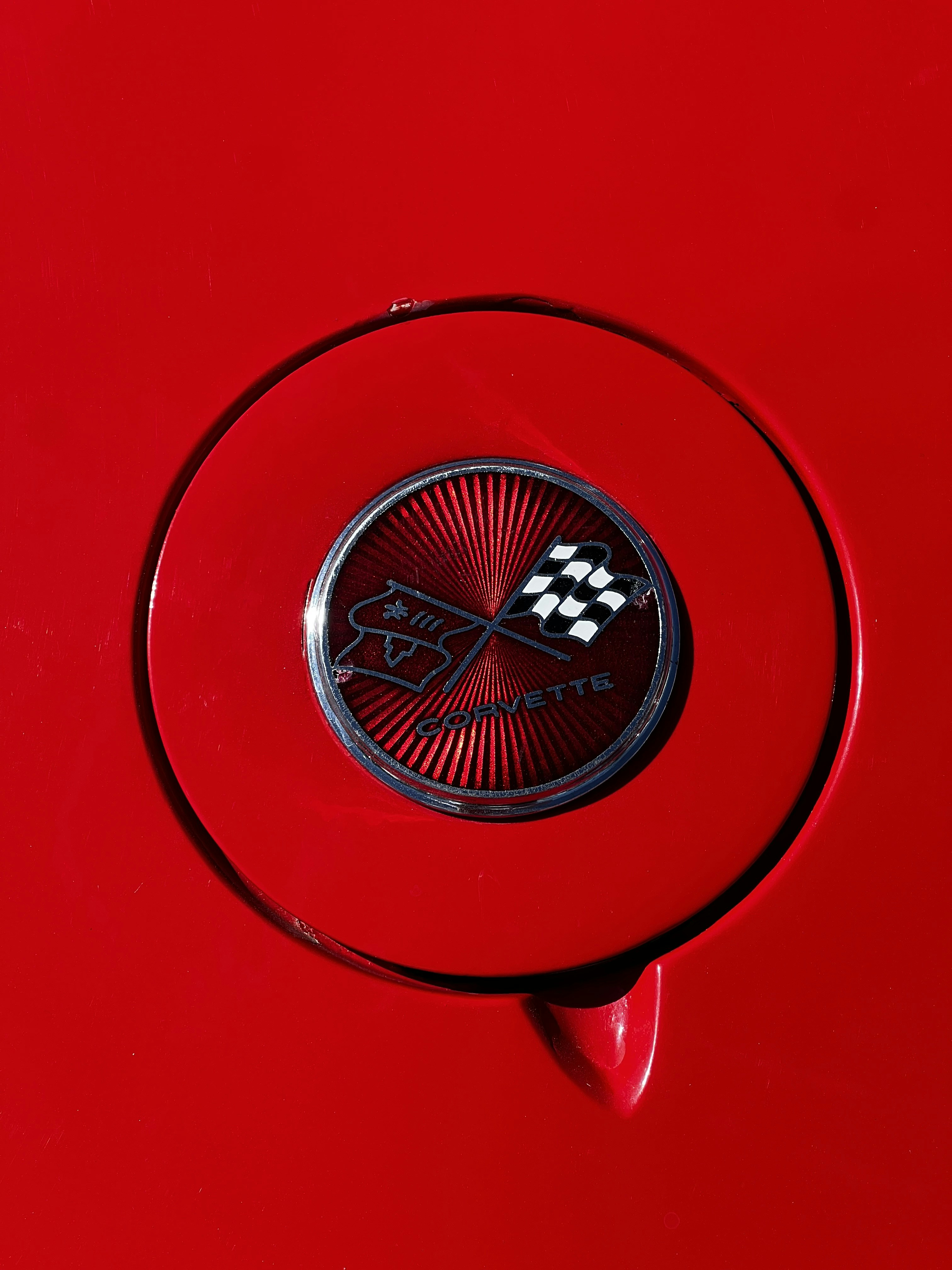 Crimson Crest: Close-Up of a Corvette Emblem on Glossy Red