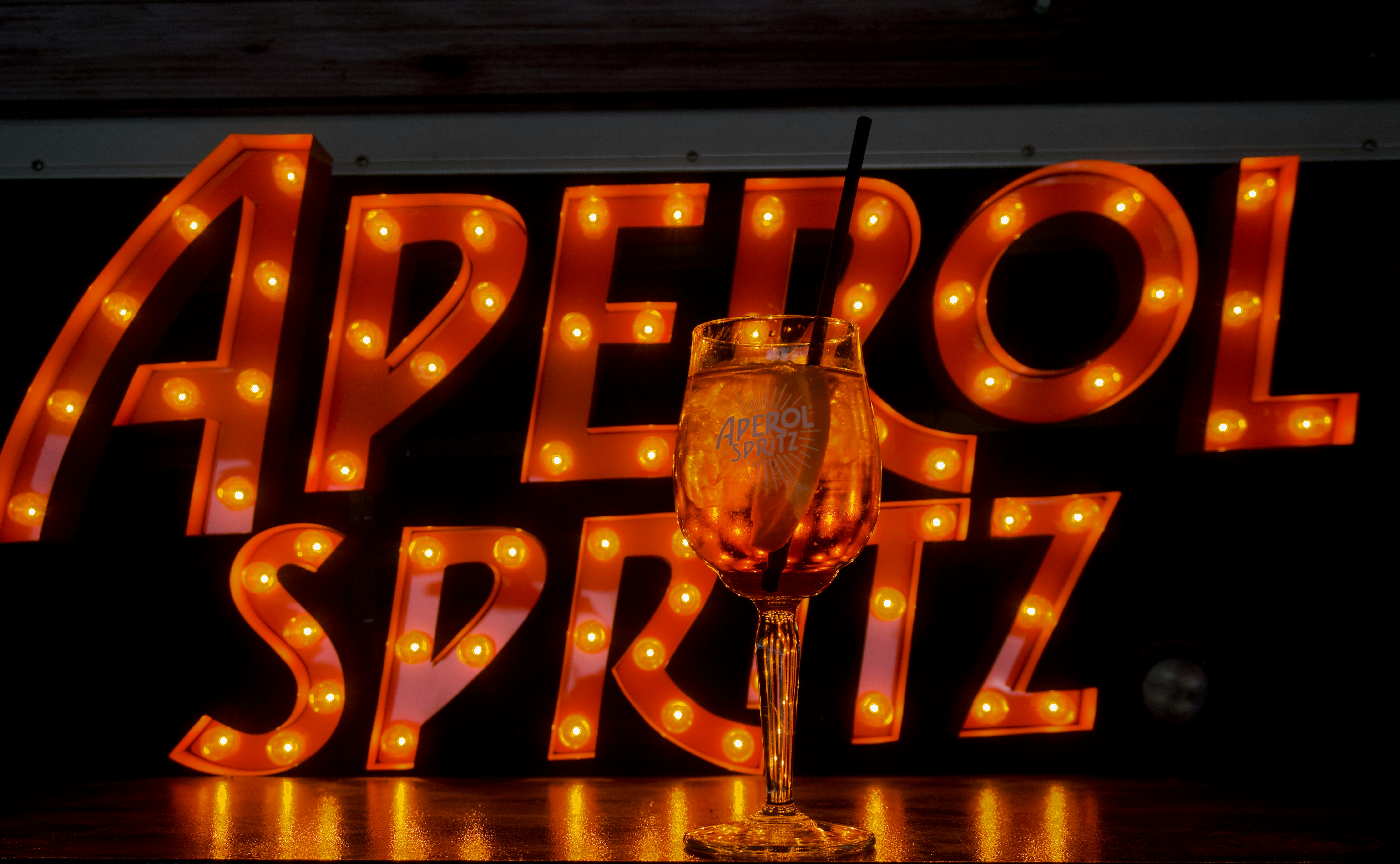 Amber Neon Over a Glass: Retro Aperol Spritz Sign Backdrop