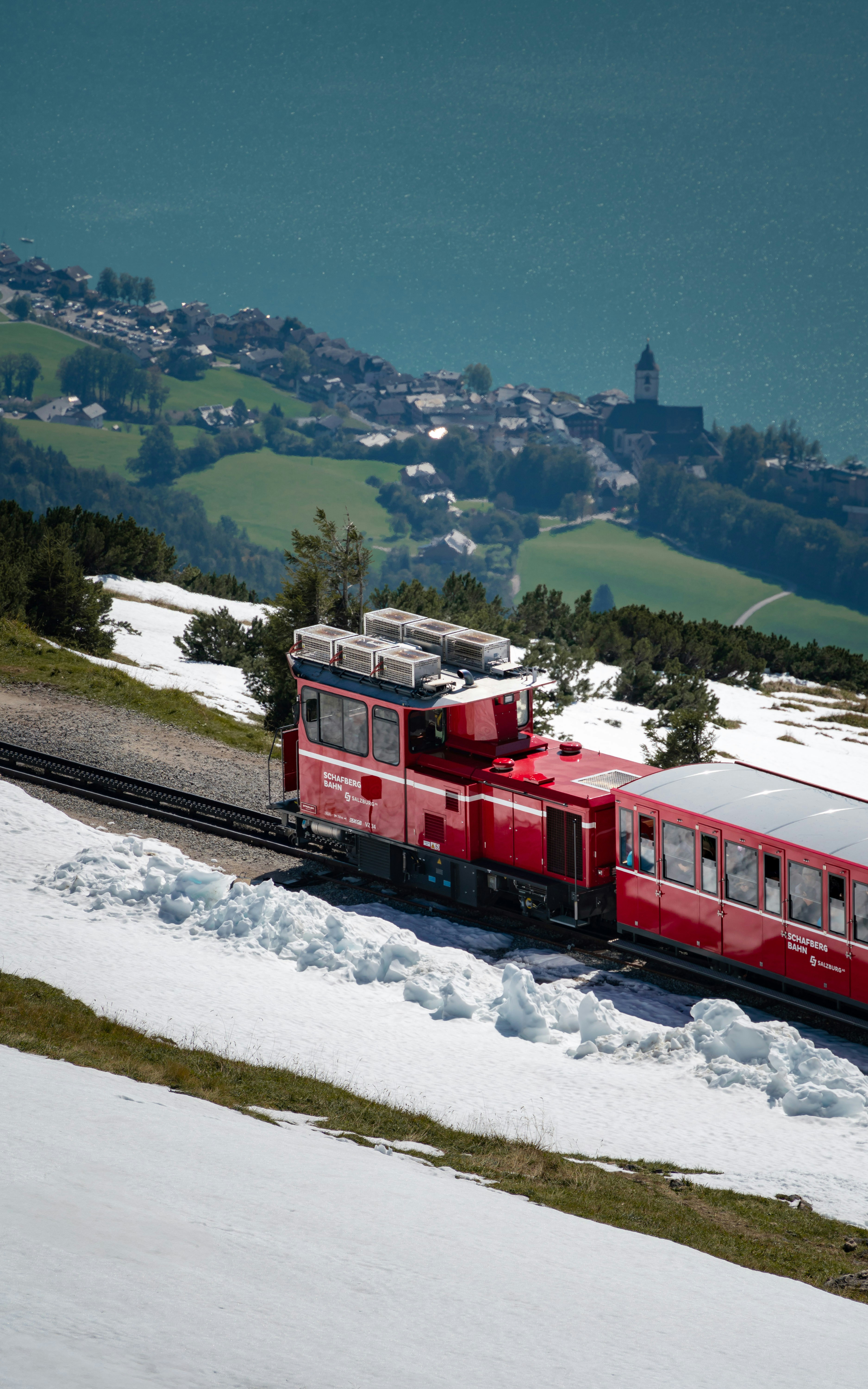 A red train traveling down train tracks next to snow covered ground ...