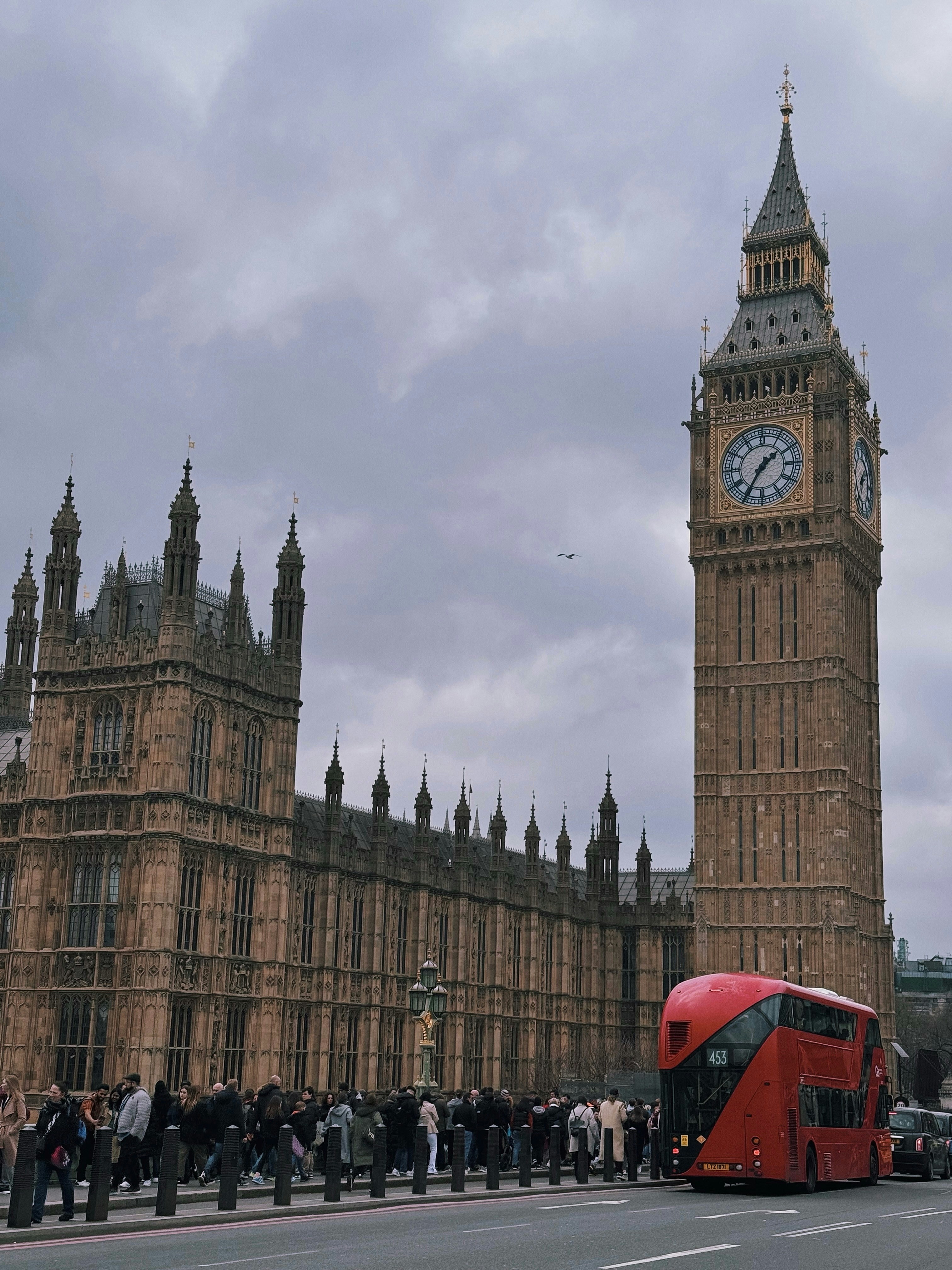 Foto Sebuah bus bertingkat merah melaju melewati menara jam tinggi ...