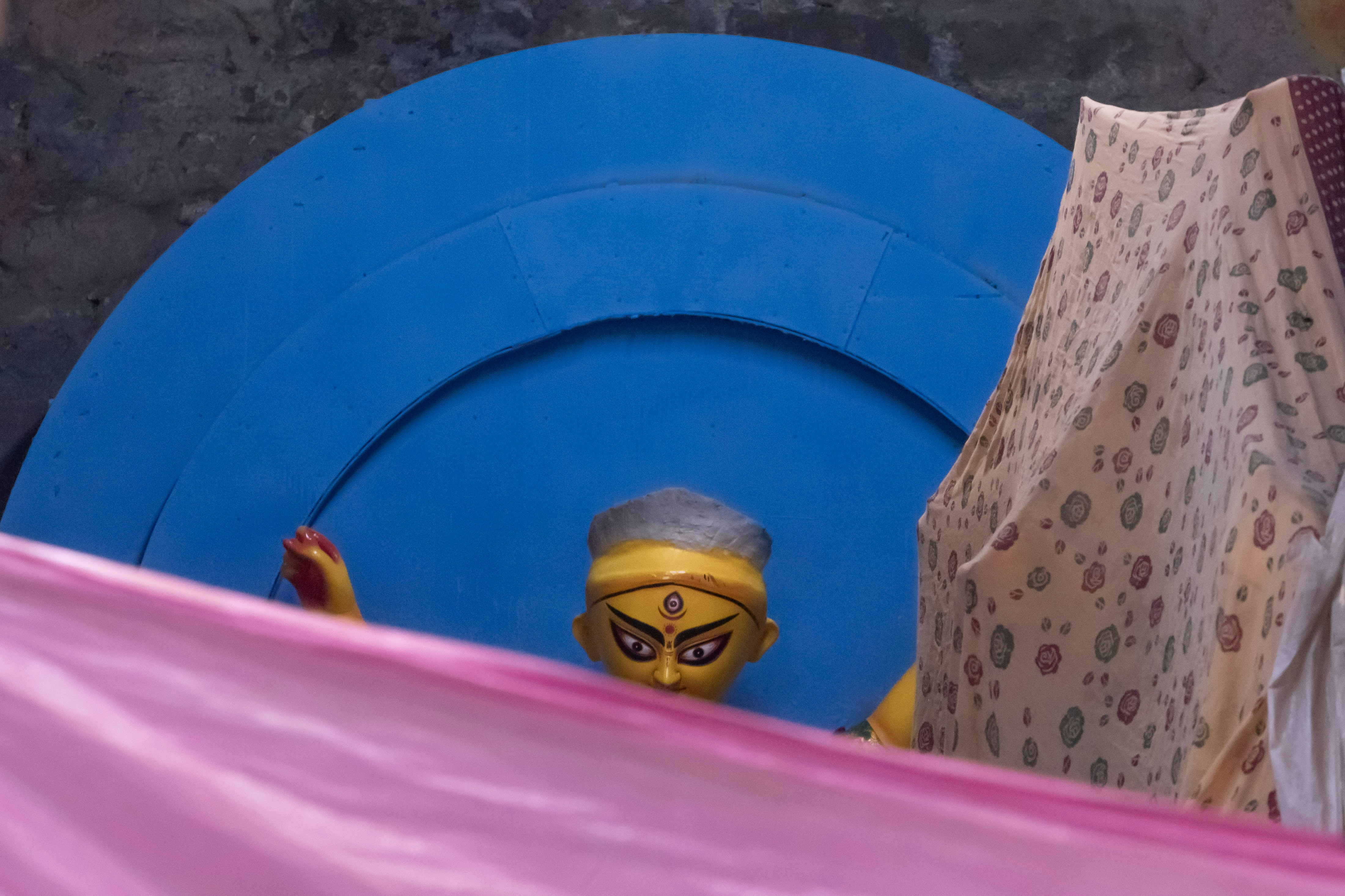 Blue Circles and Hidden Gaze: Masked Figure Peers from Behind Draped Fabric