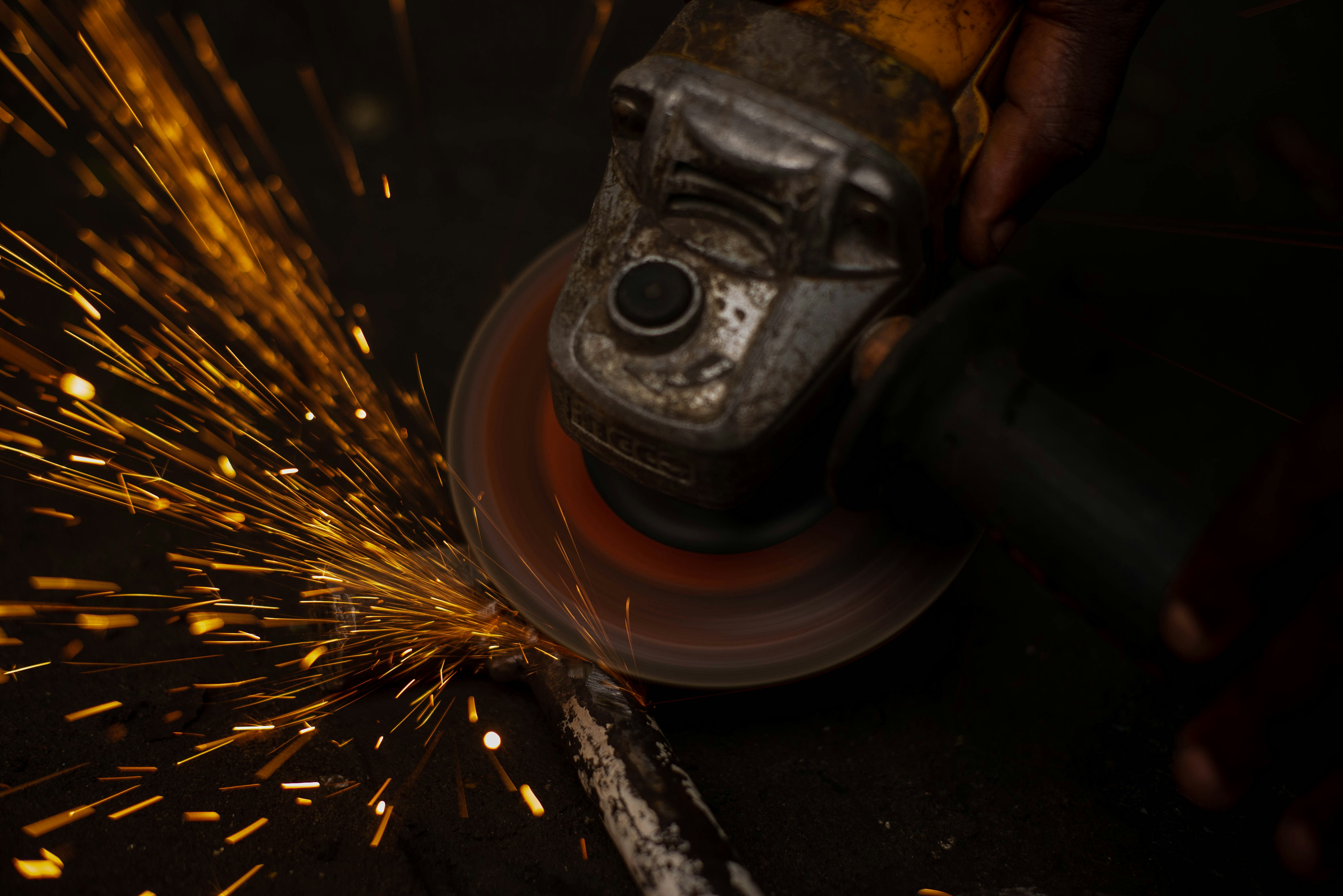 A person using a grinder on a piece of metal photo – Free Work Image on ...