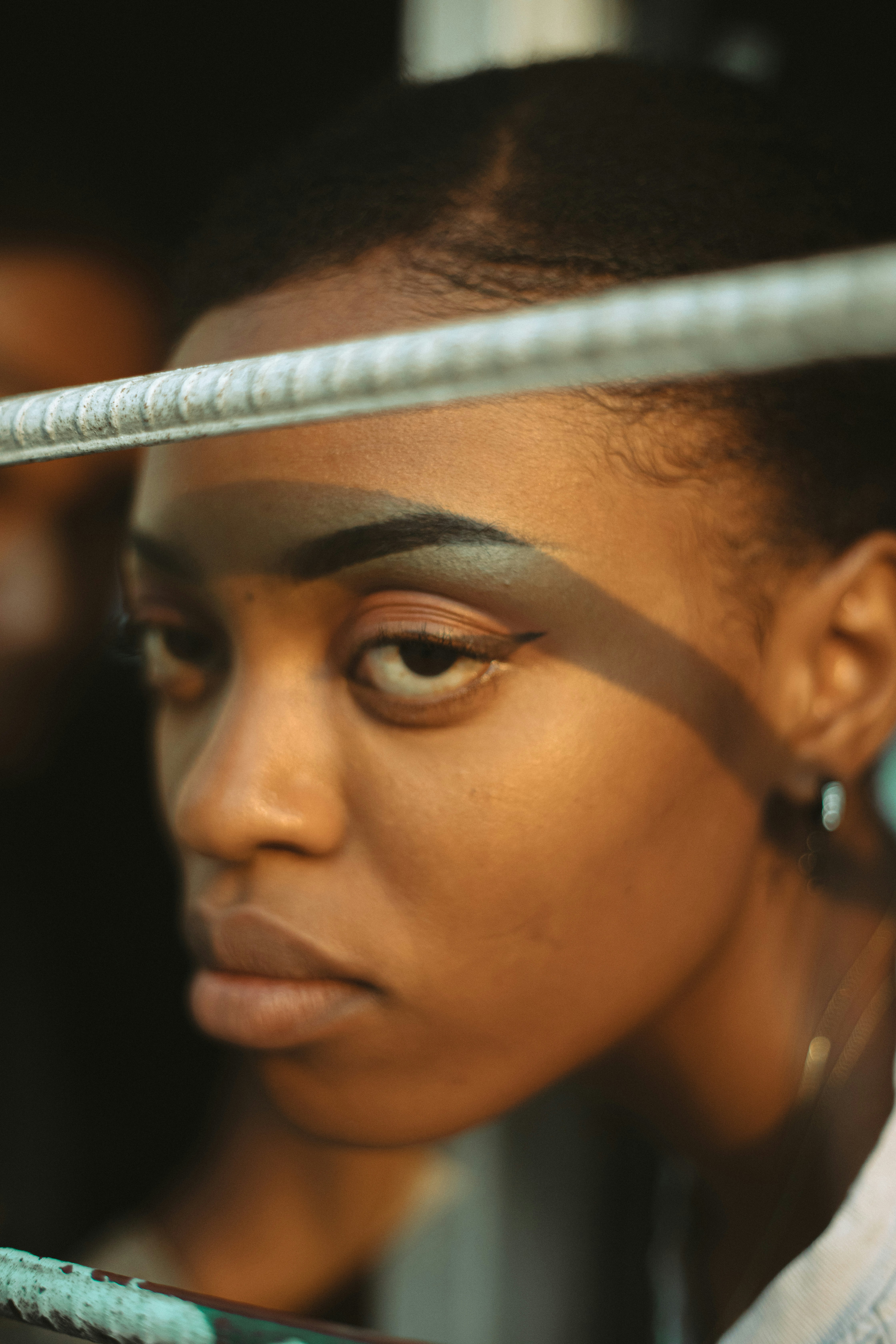 Gaze Framed by a Bar: a close-up portrait in warm, shadowed light