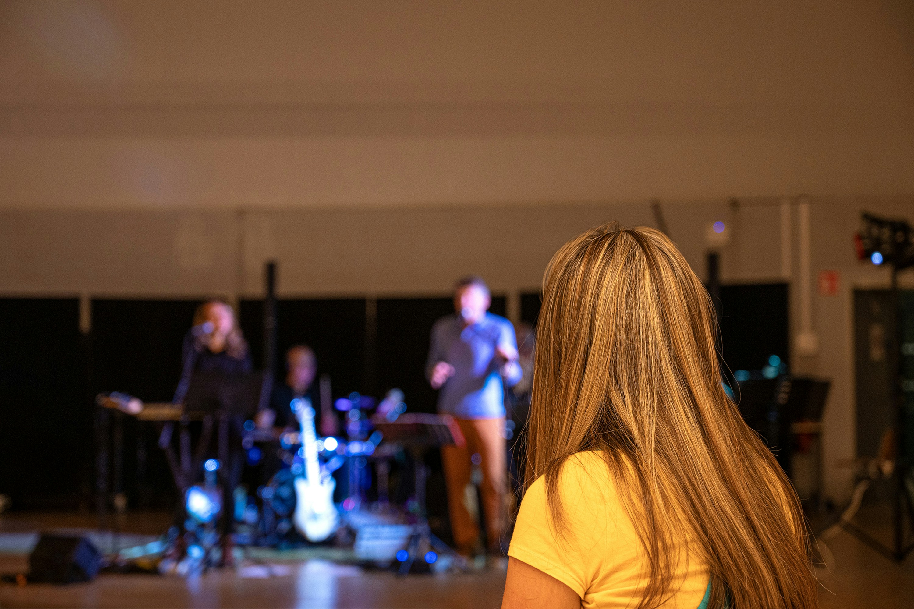 Front-row Reflection: A Woman in a Yellow Shirt Watching a Live Band