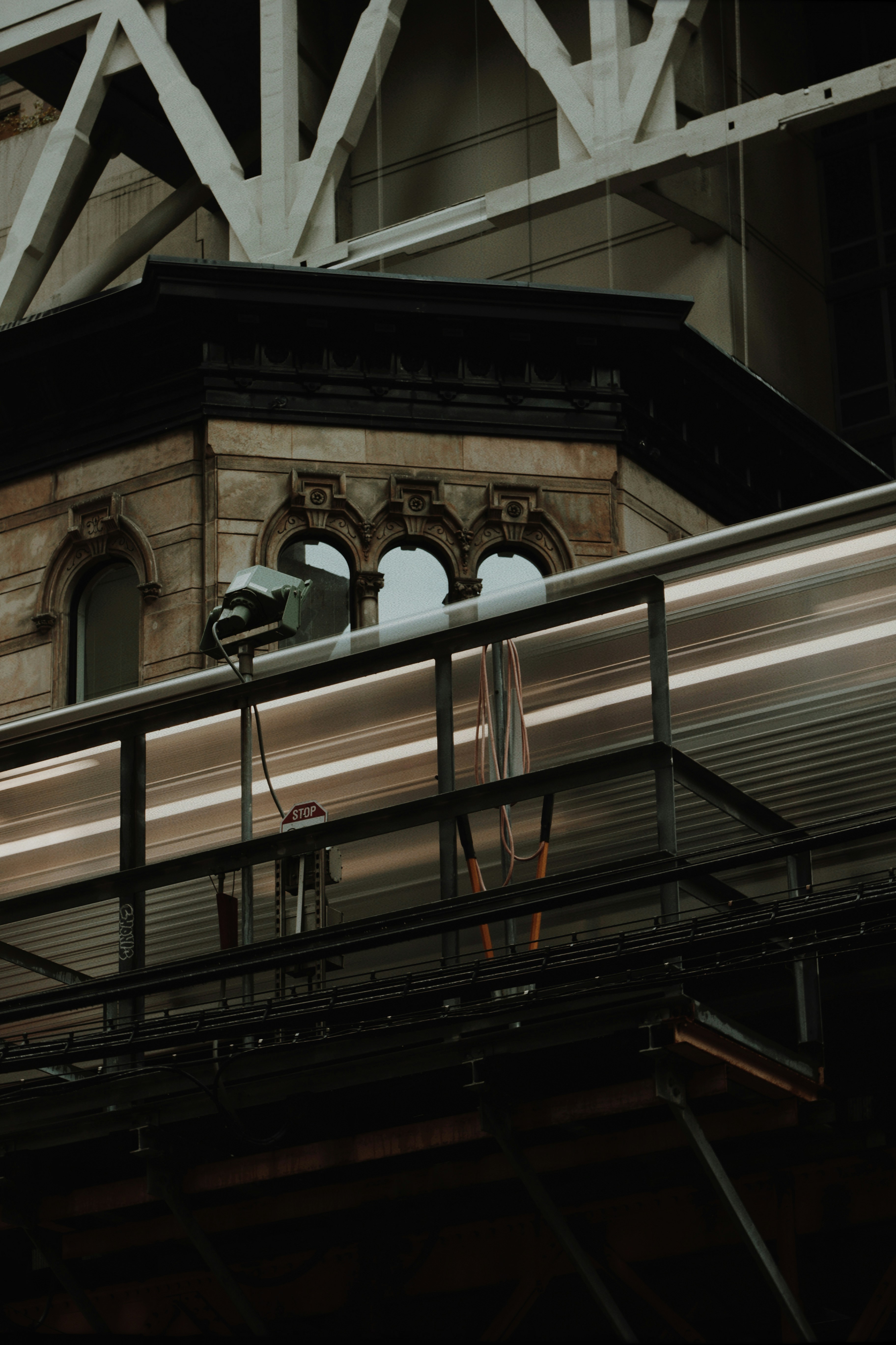 A train traveling past a tall building under a bridge photo – Free ...