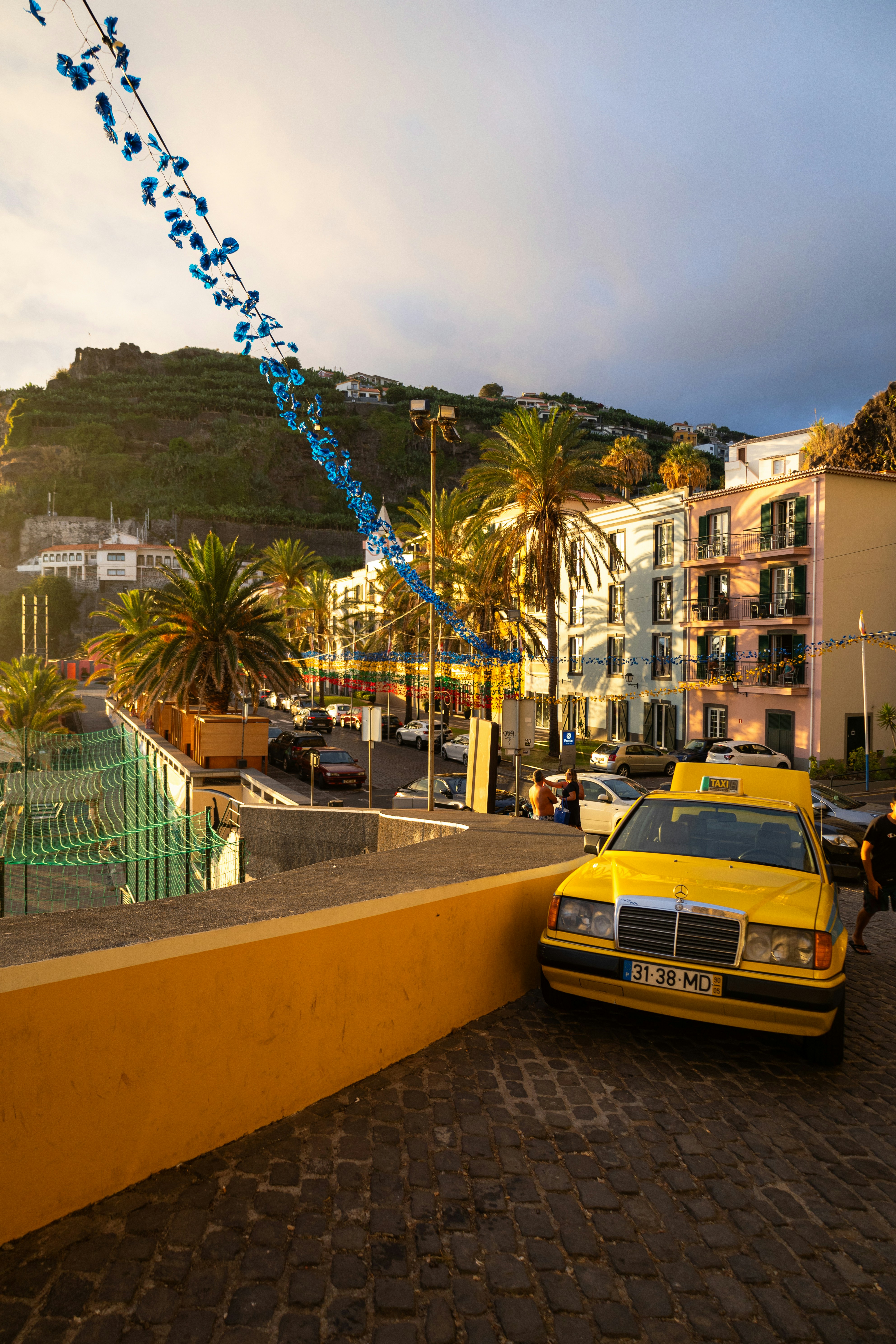 Sunlit Riviera Street: Yellow Taxi Anchors a Hillside Coastal Town