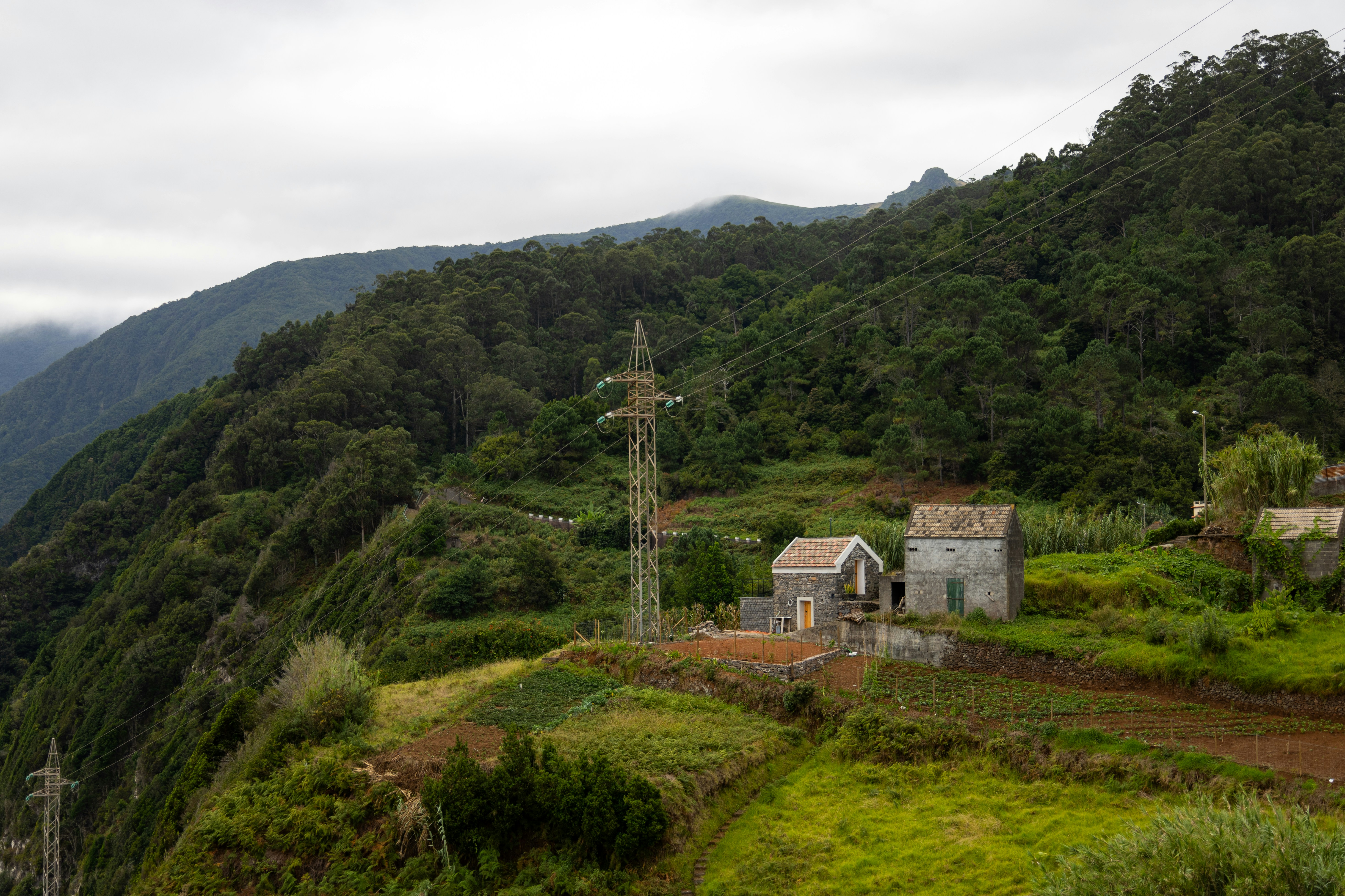 Terraced Hillside Village Under a Lone Lattice Transmission Tower