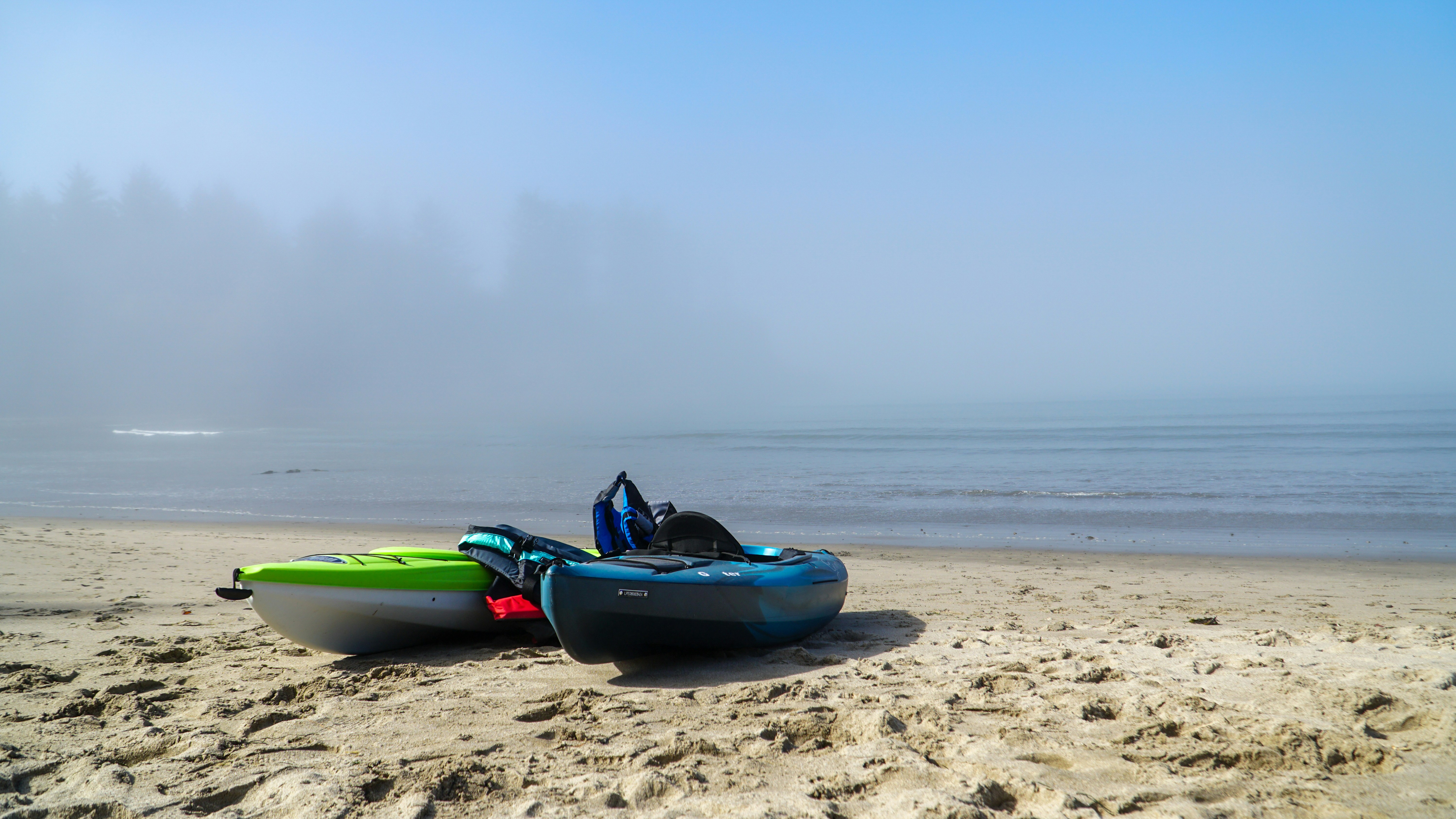 Dawn Fog Over a Quiet Shore: Lime and Navy Kayaks Rest on Sand
