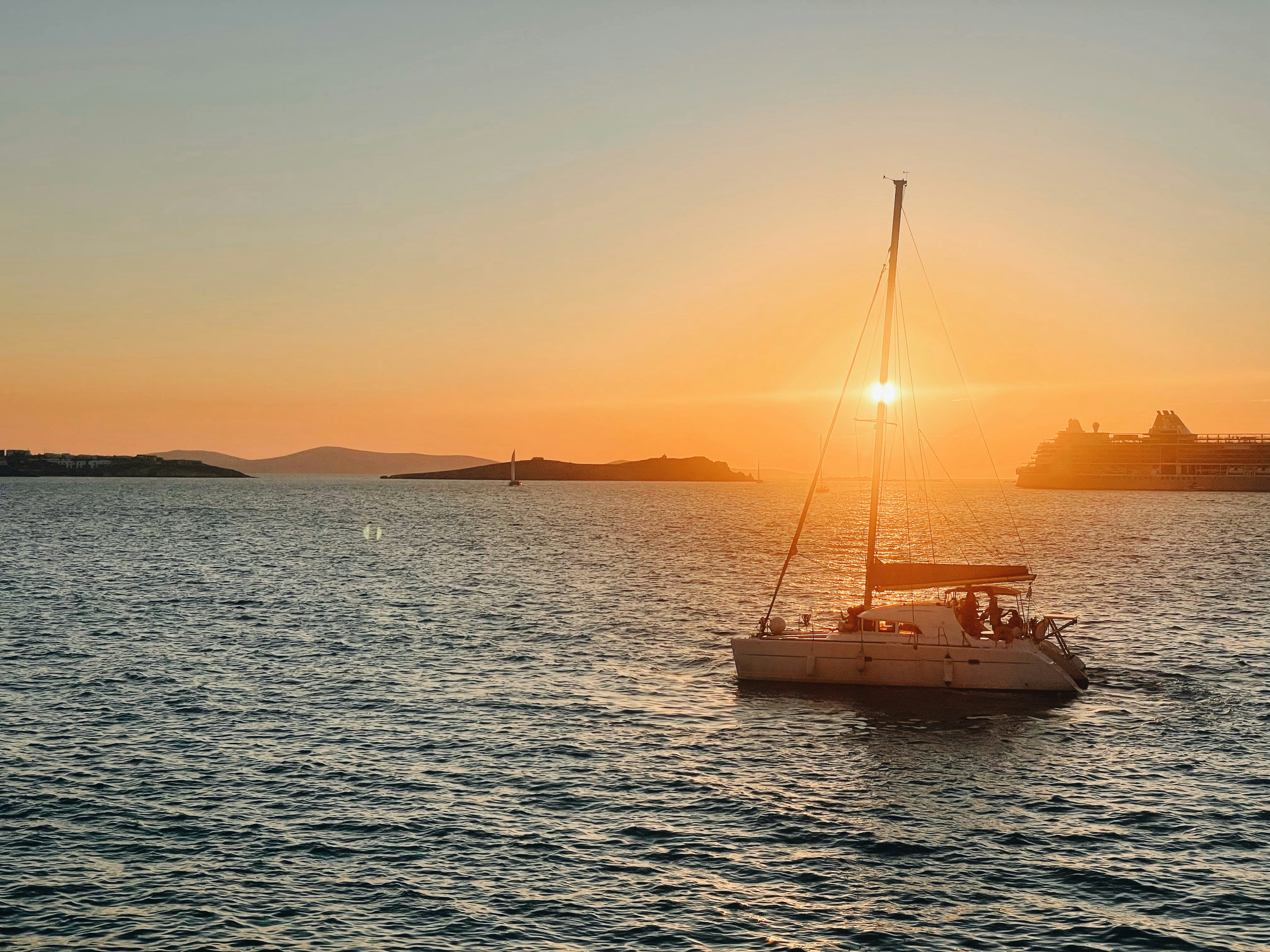 Sunlit Sail: A lone boat drifting toward the glow of a coastal sunset