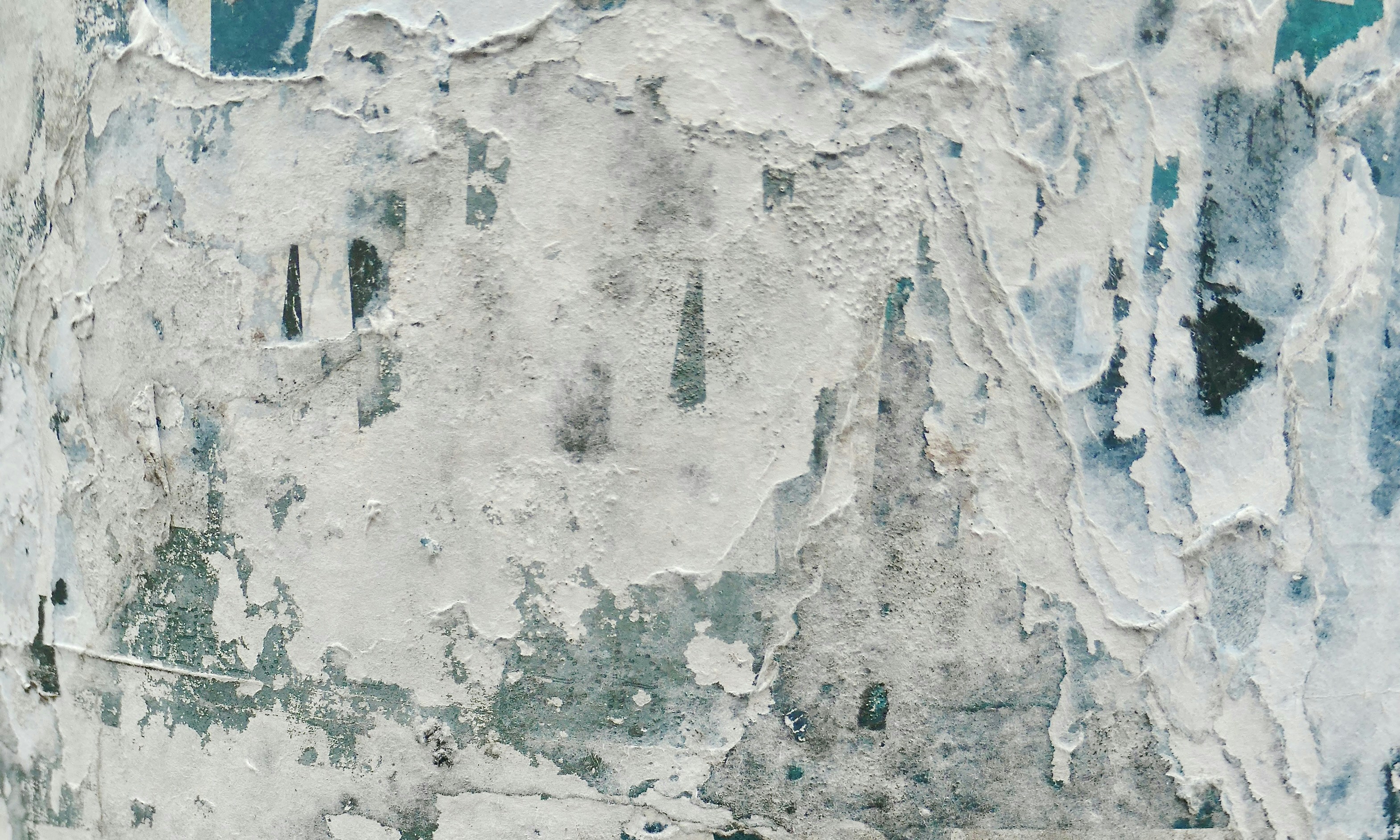 Textured abstract pattern of peeling paint on a weathered wall with shades of gray and blue.