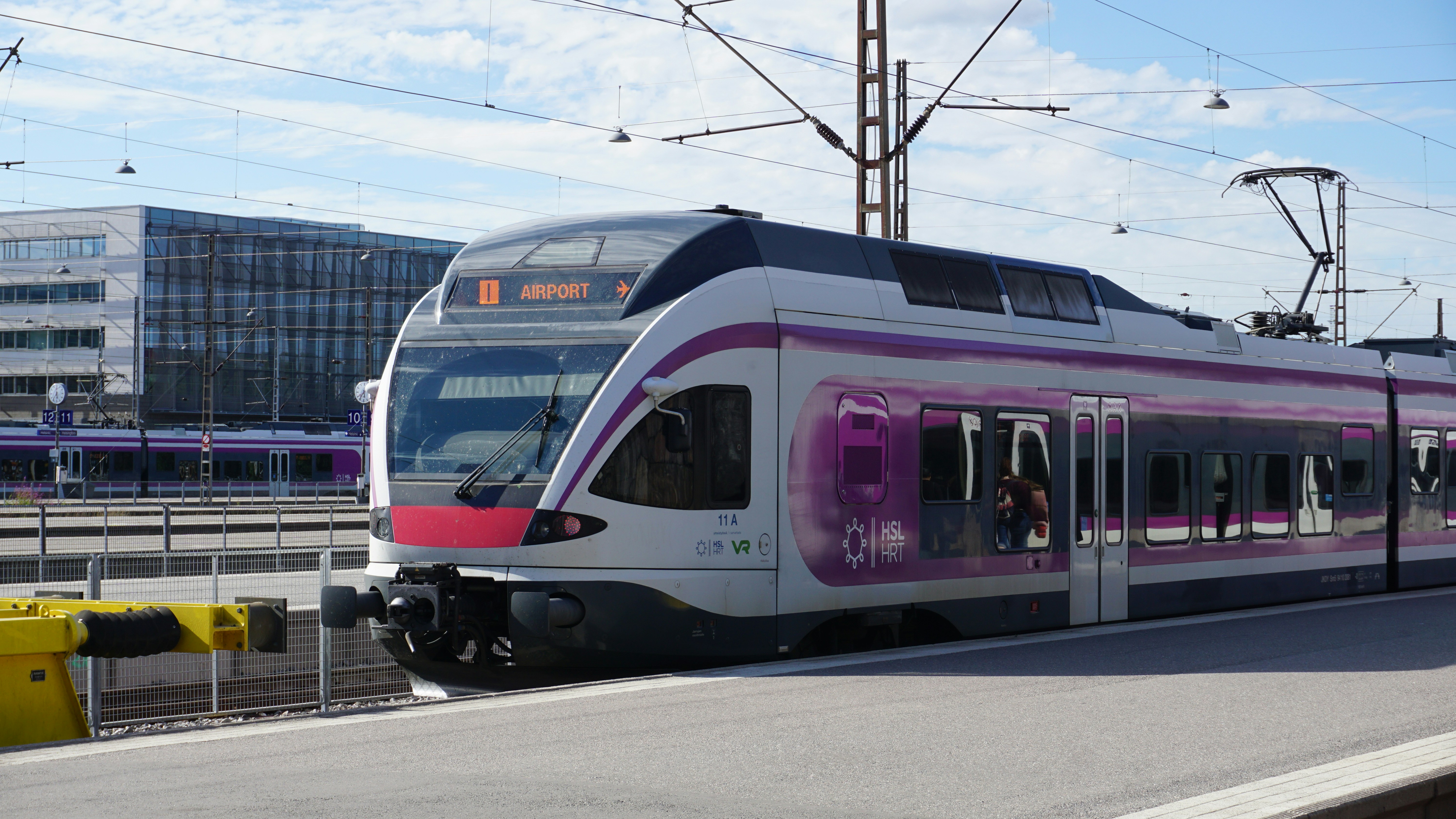 Purple stripe train at platform gliding toward the city