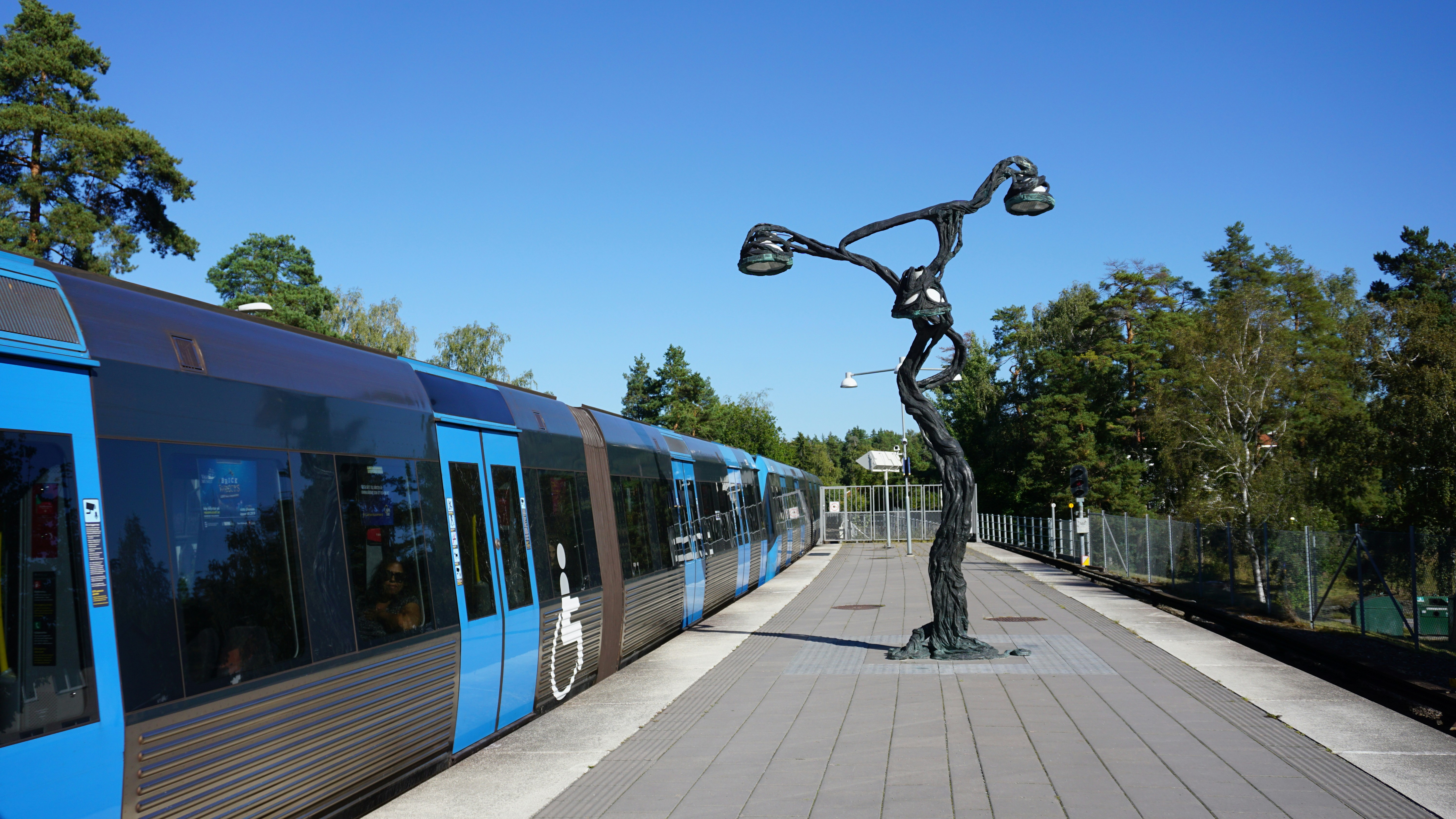 Iron Dancer on a Blue Platform Beside a Quiet Train