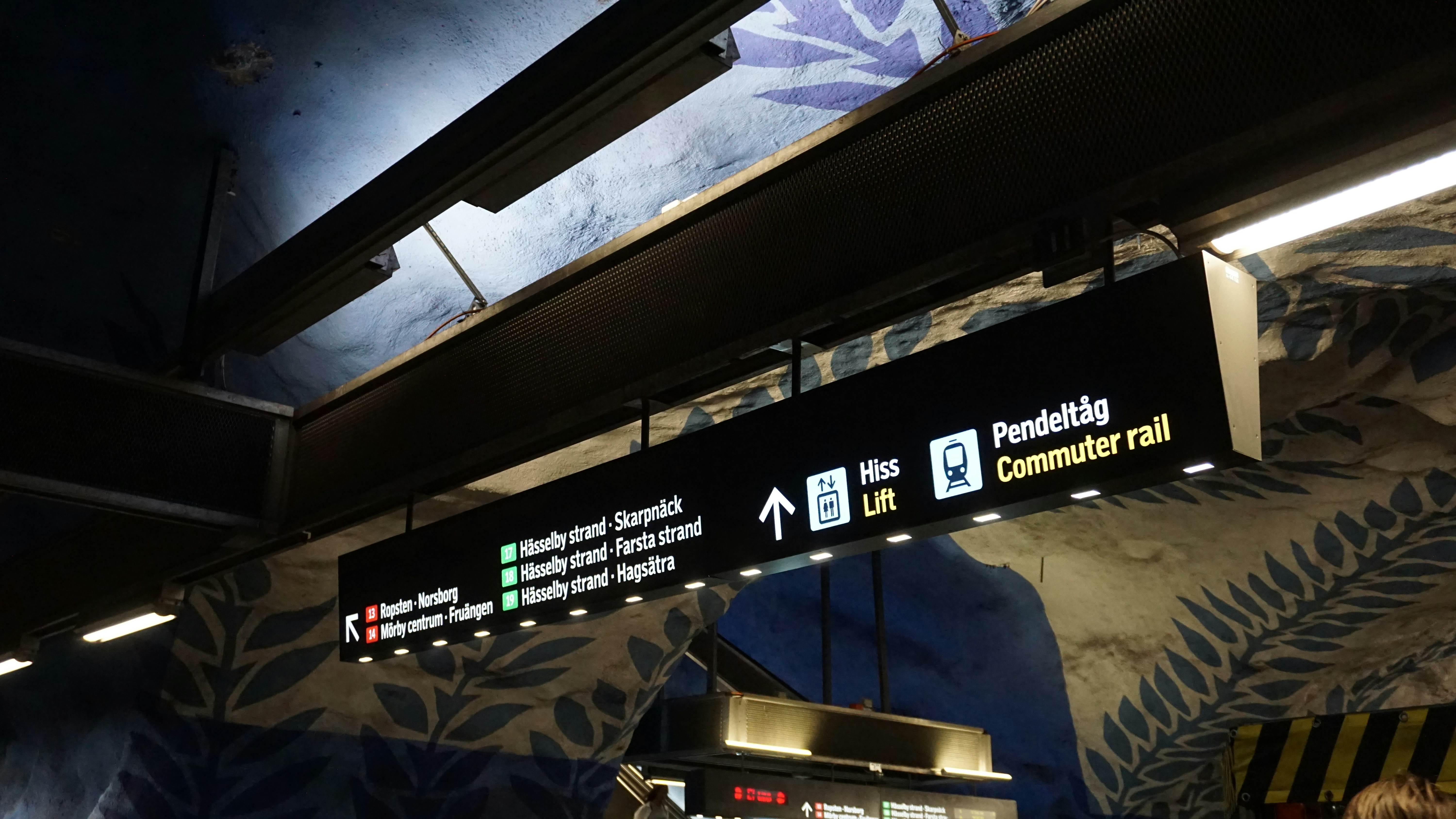 A train station with a sign and a person on the platform photo – Free T ...