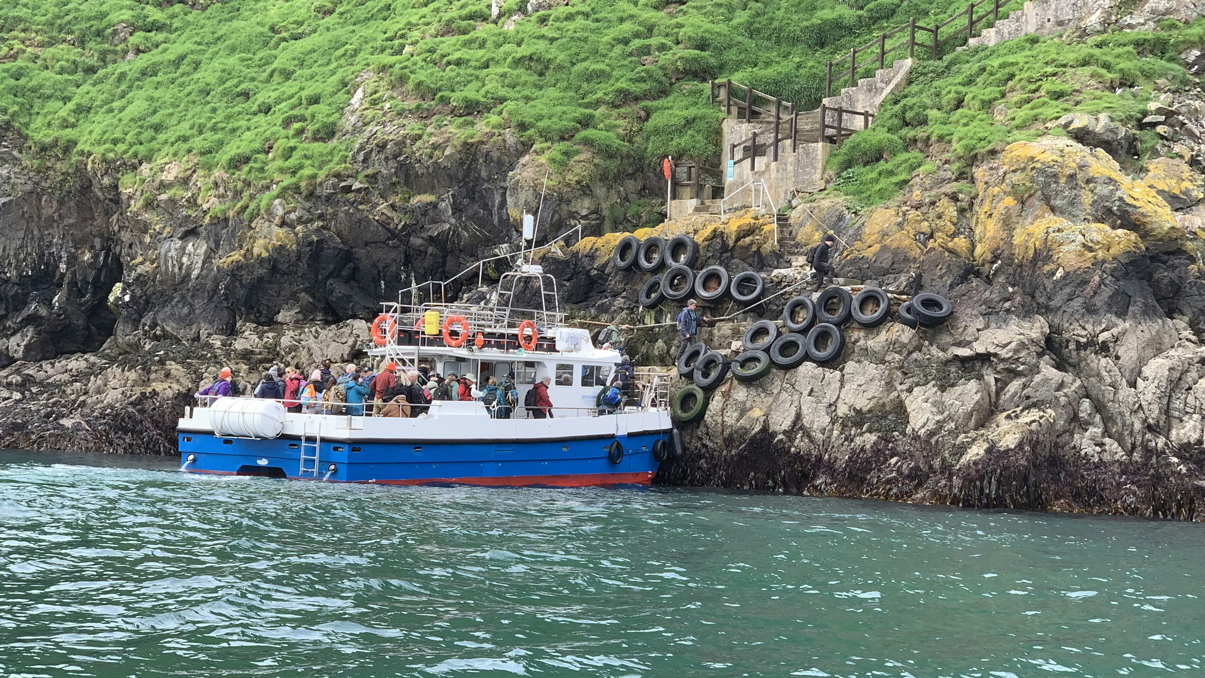 Blue Passenger Boat Tied to a Tire-Stacked Sea Wall