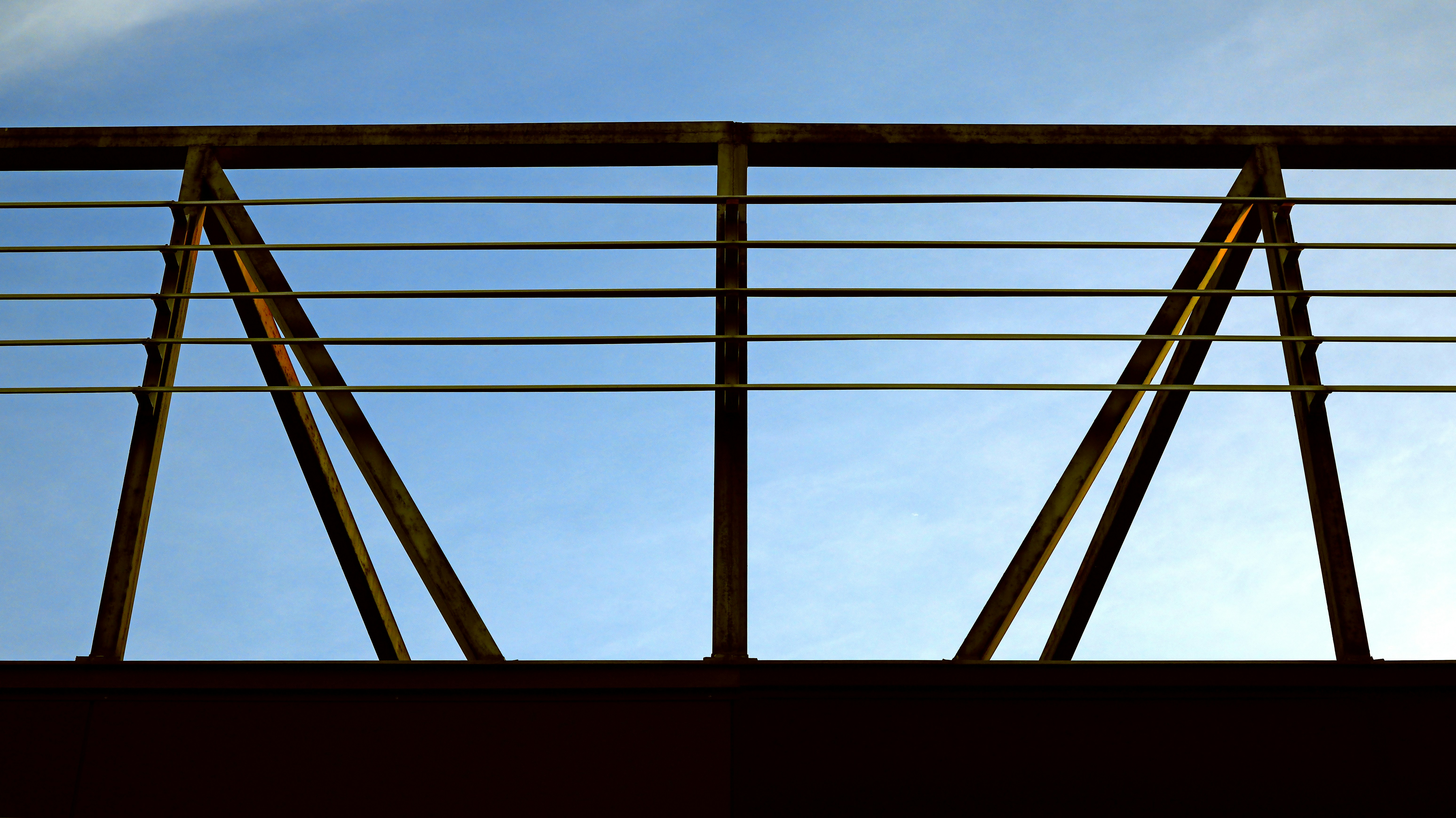 A bird flying over a bridge with a blue sky in the background photo ...
