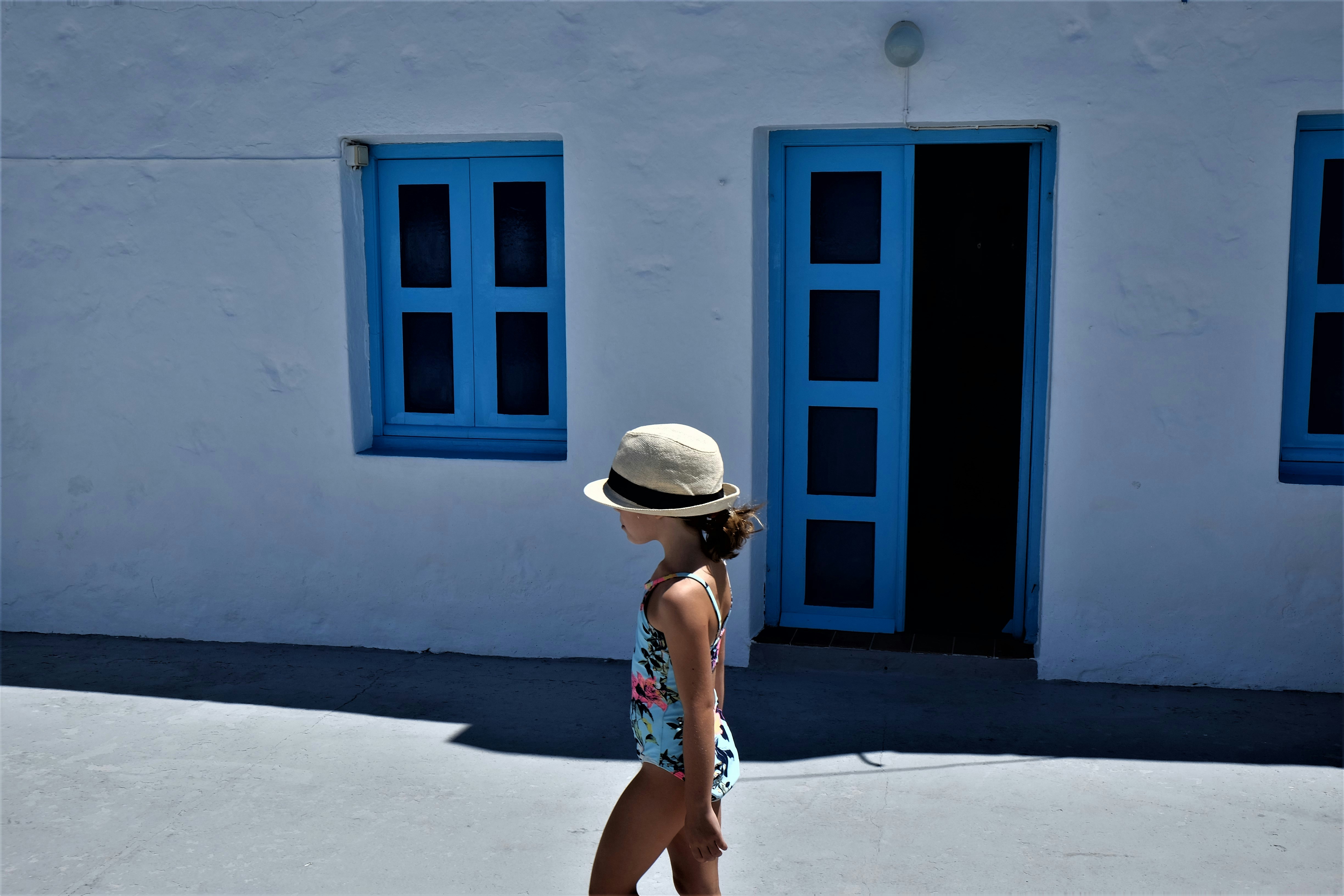 Sunlit Wanderer Against Cobalt Doorways on a Cycladic Street