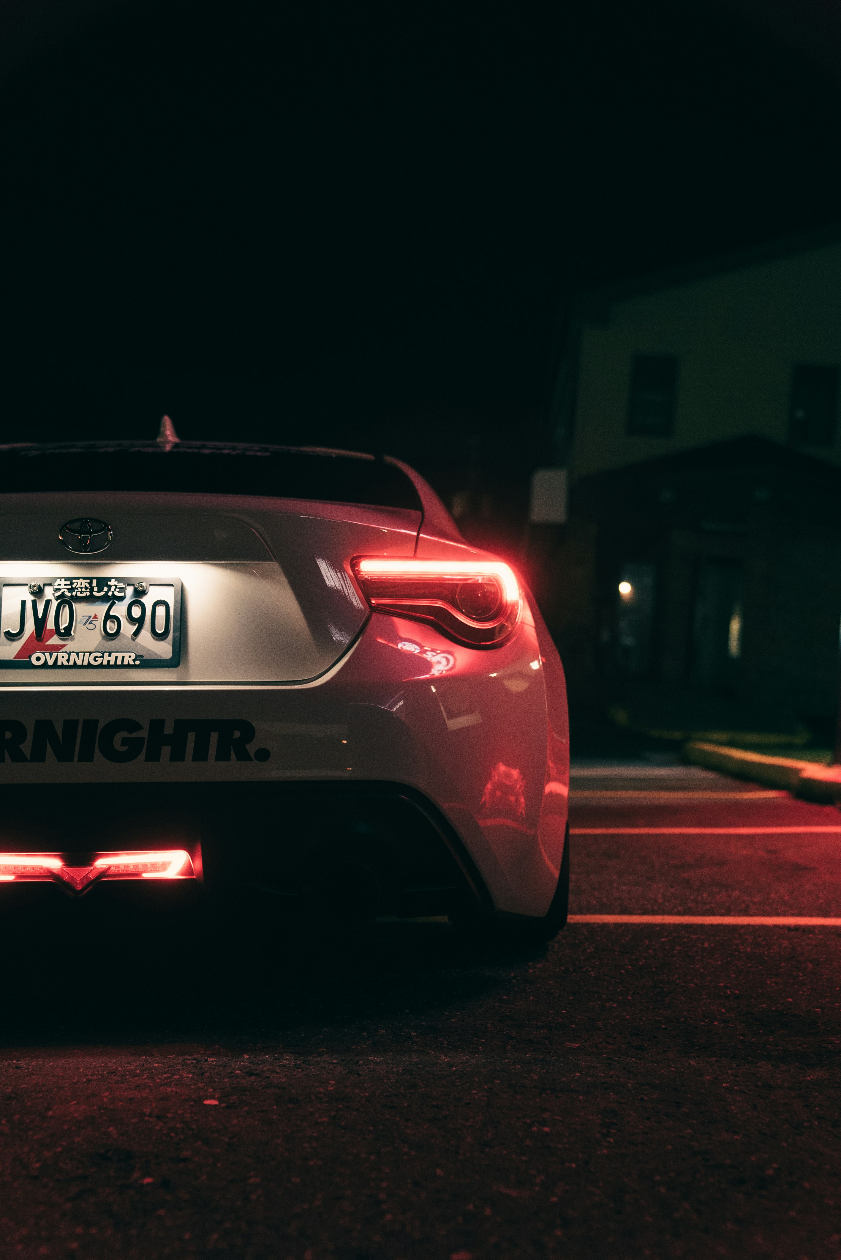 Red Taillight Reverie: A White Sports Car in a Quiet Night Parking Lot