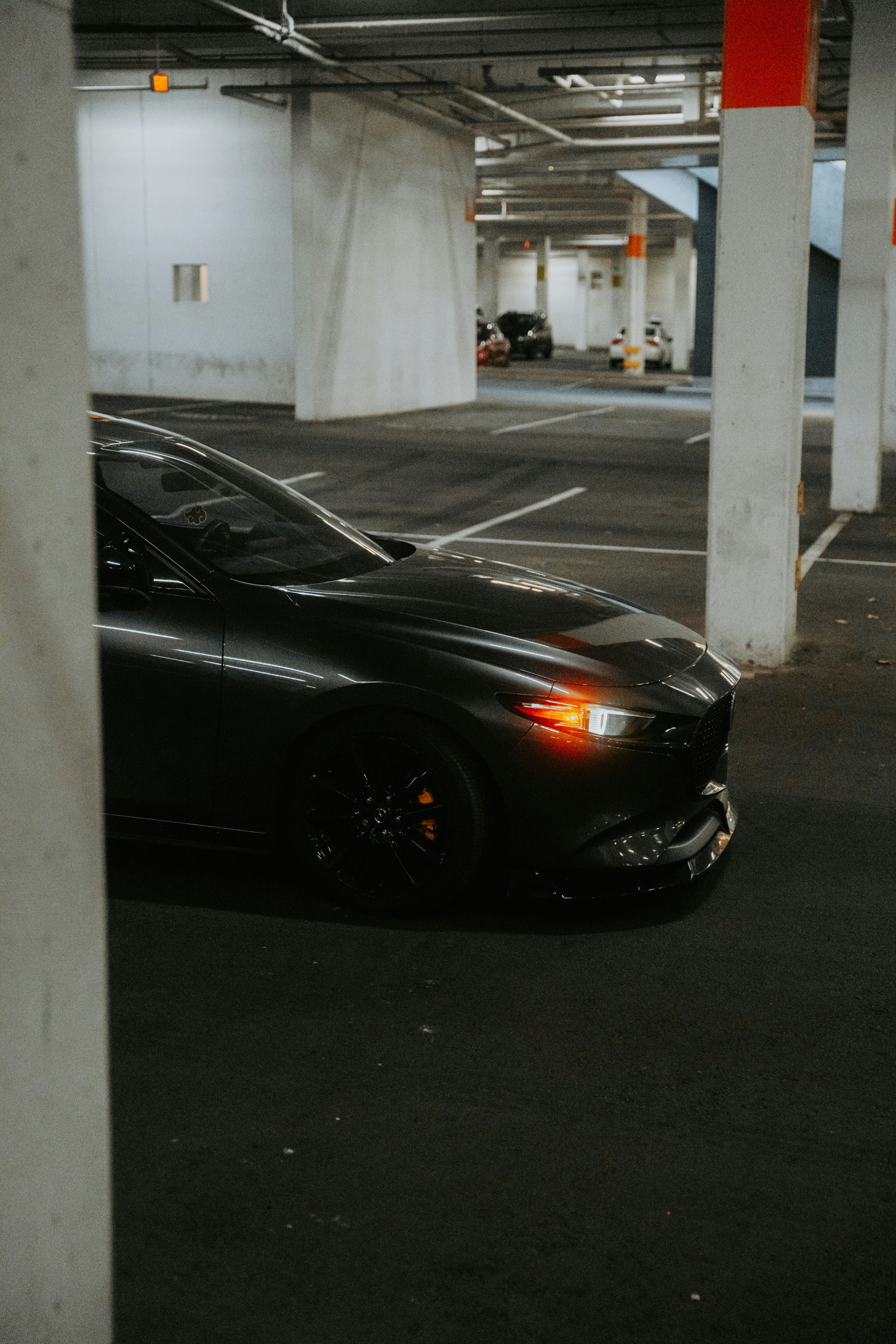 Noir in Concrete: A Black Sports Car Centered Under Industrial Garage Lighting