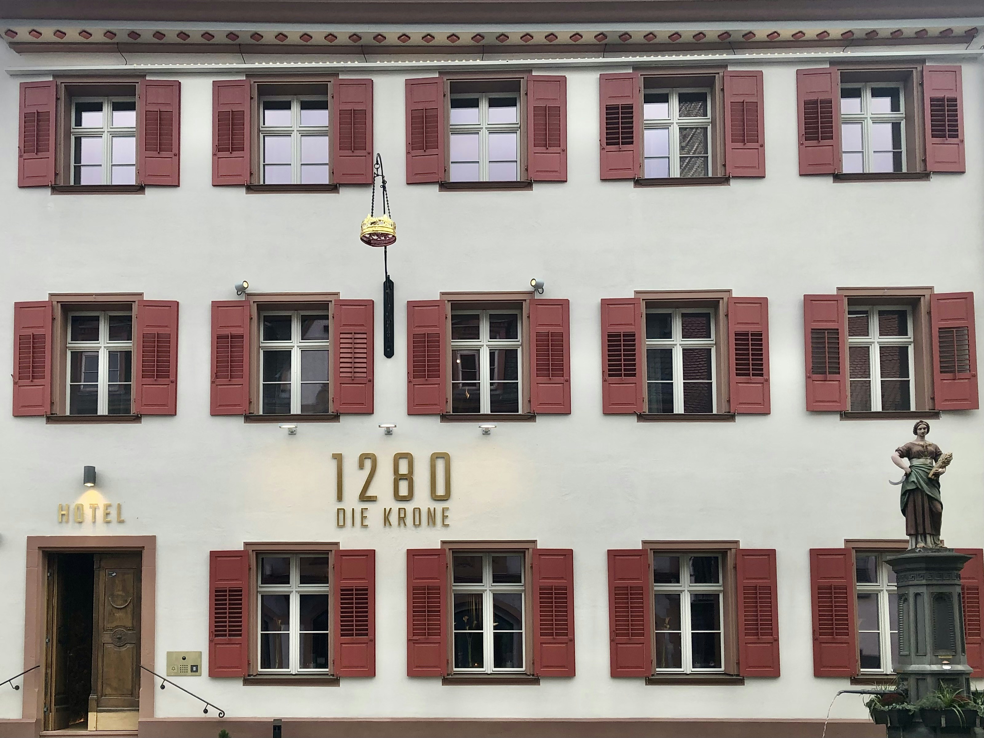 Crimson Shutters, Central Sign: The 1280 Die Krone Hotel Facade
