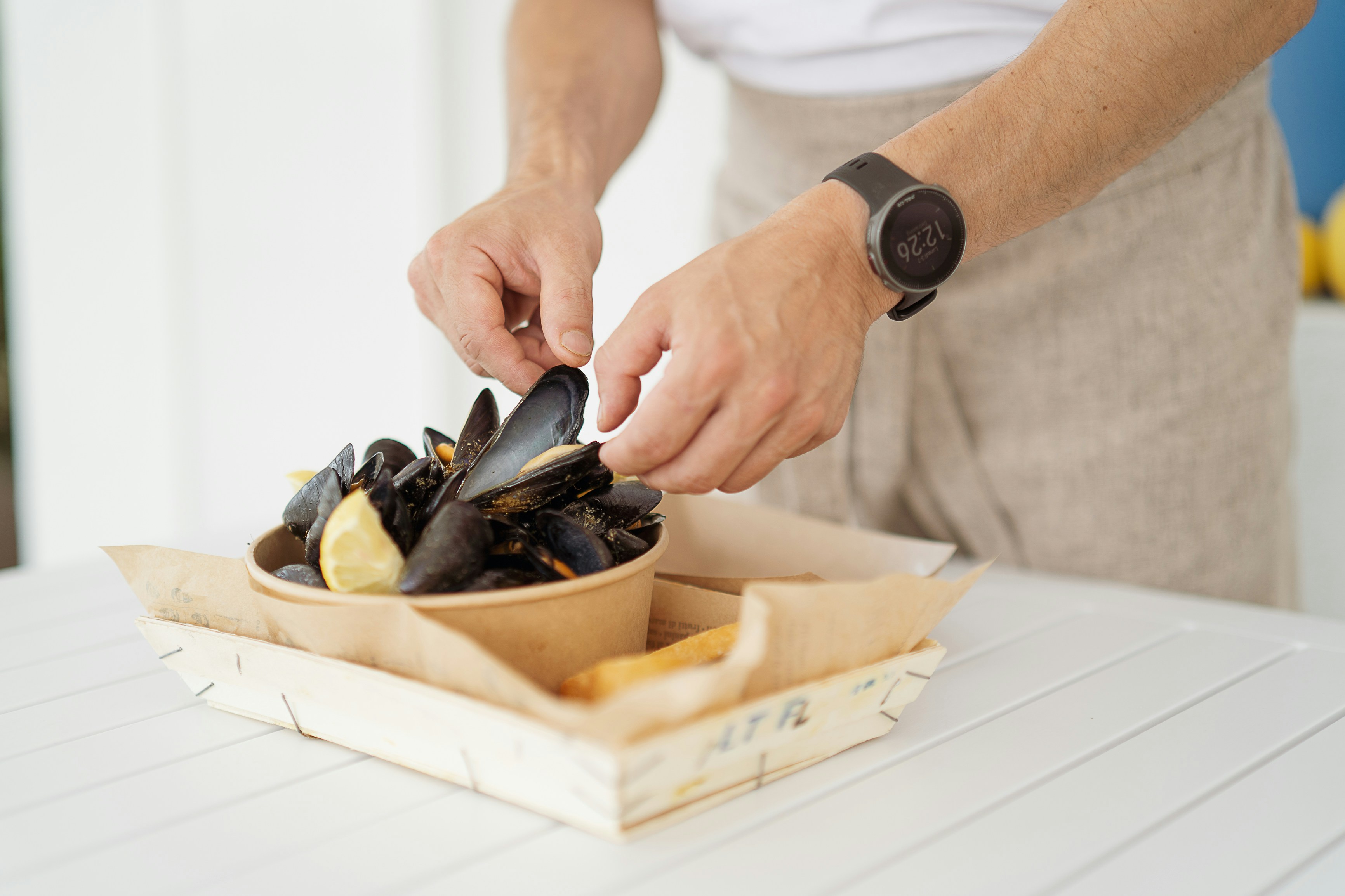A man standing over a bowl of mussels on top of a table photo – Free ...