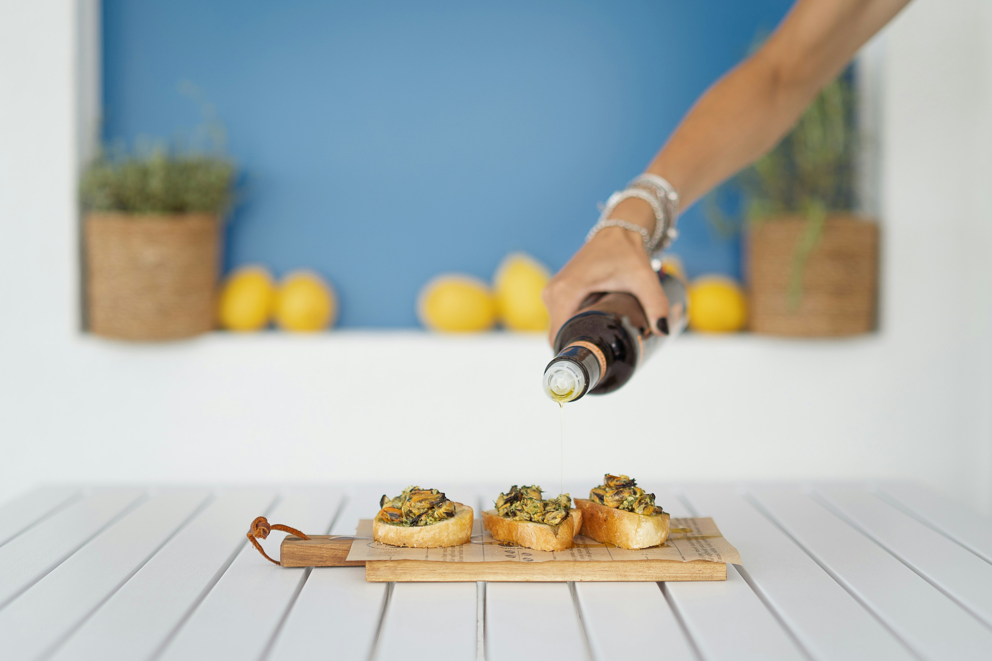 Olive oil mist crowns herb crostini on a sunlit board