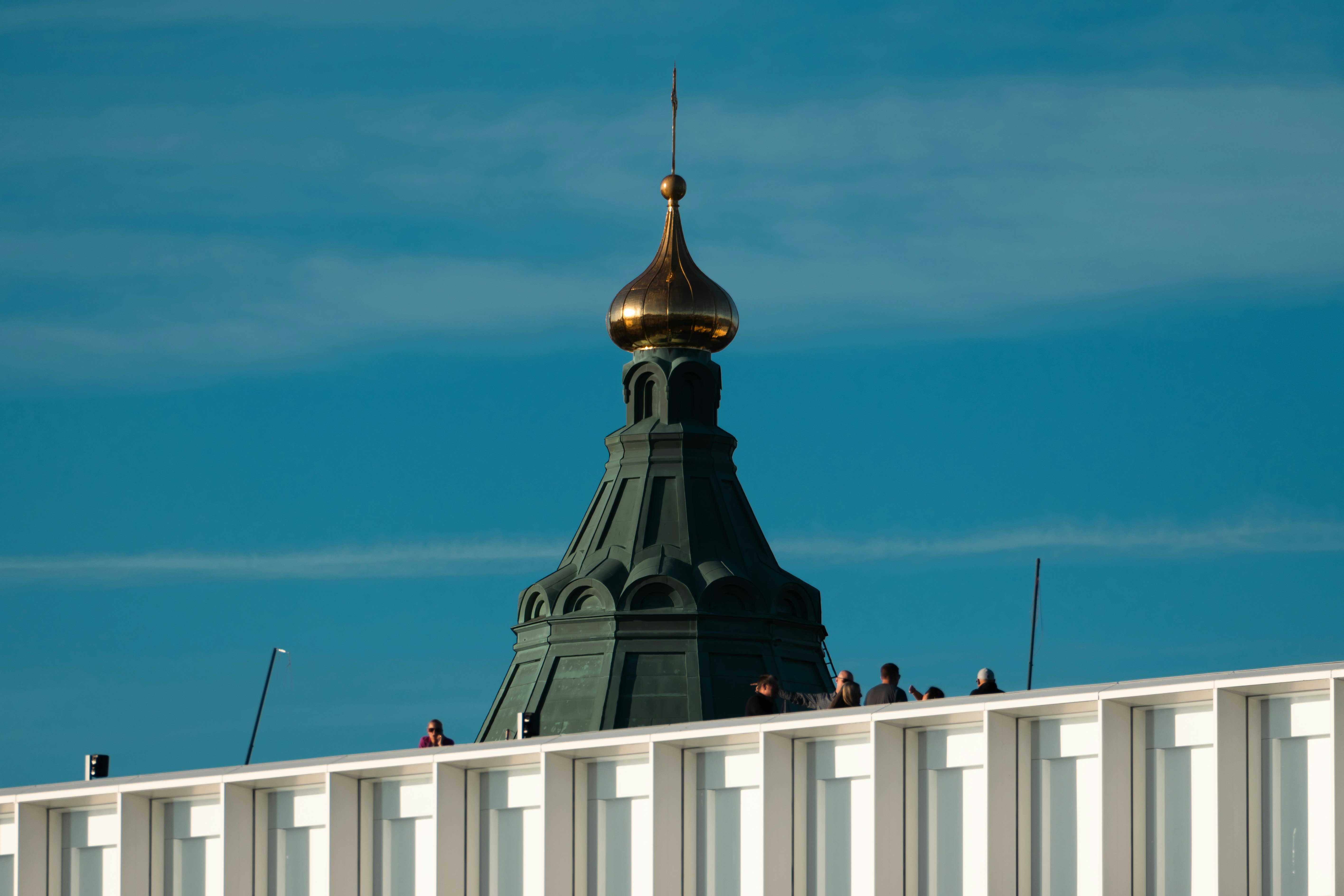 Golden Onion Dome Rising Above Verdigris Turret Against a Stark Blue Sky