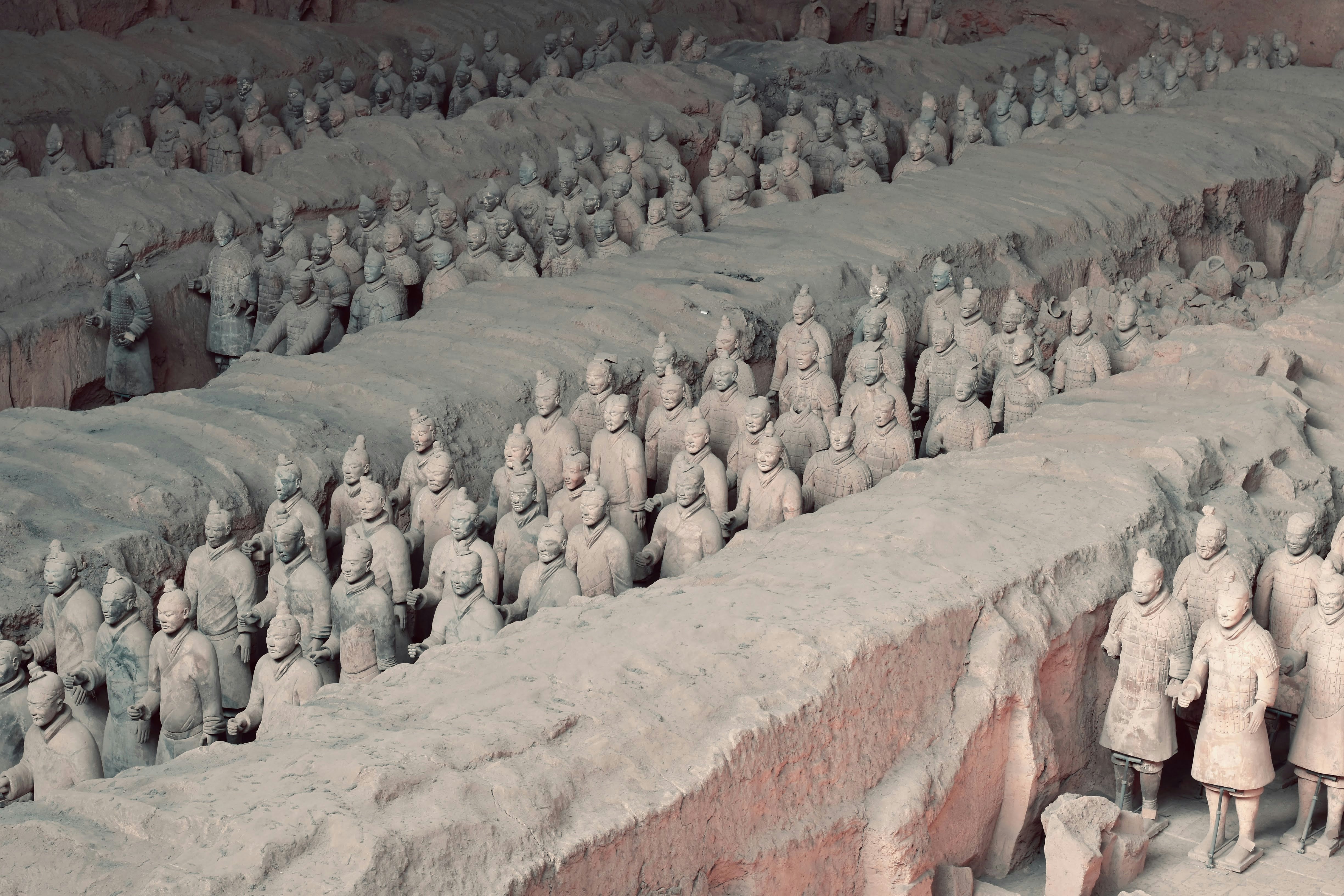 Terracotta warriors standing in rows within an archaeological excavation site.