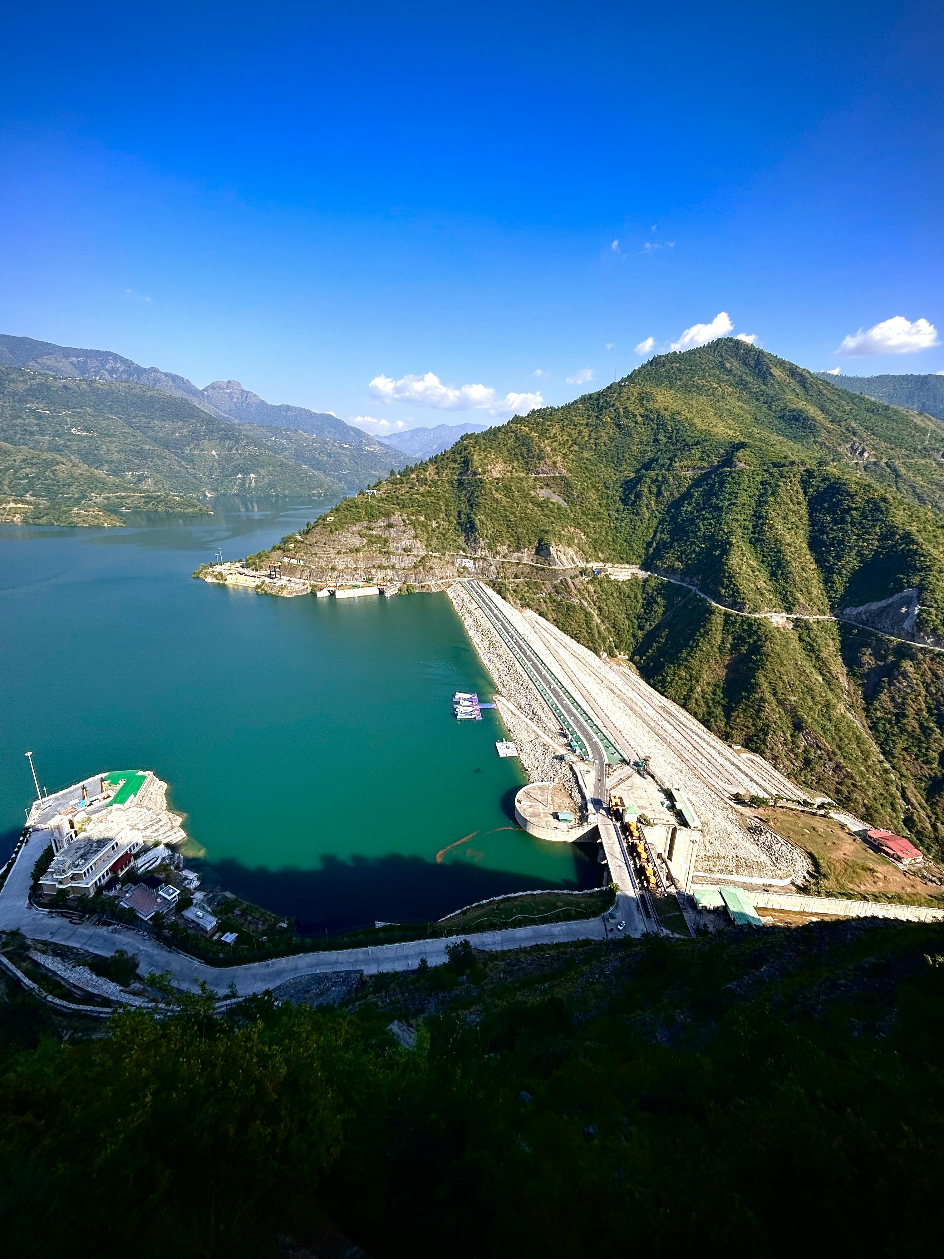 The Spine of the Gorge: A Concrete Dam Crossing Verdant Mountains Over a Turquoise Lake