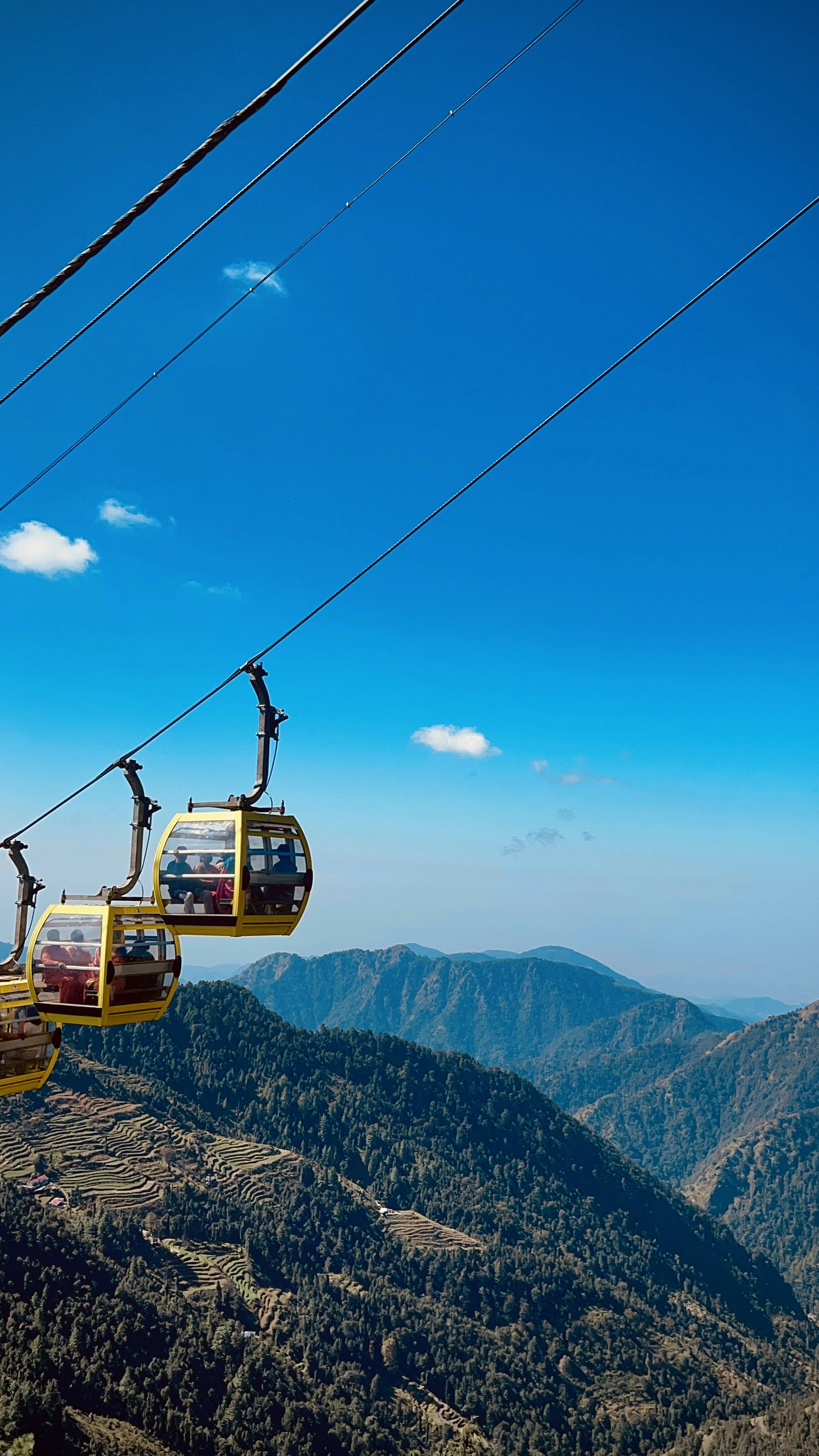Yellow Cable Cars Glide Above Terraced Peaks Beneath a Brilliant Blue Sky