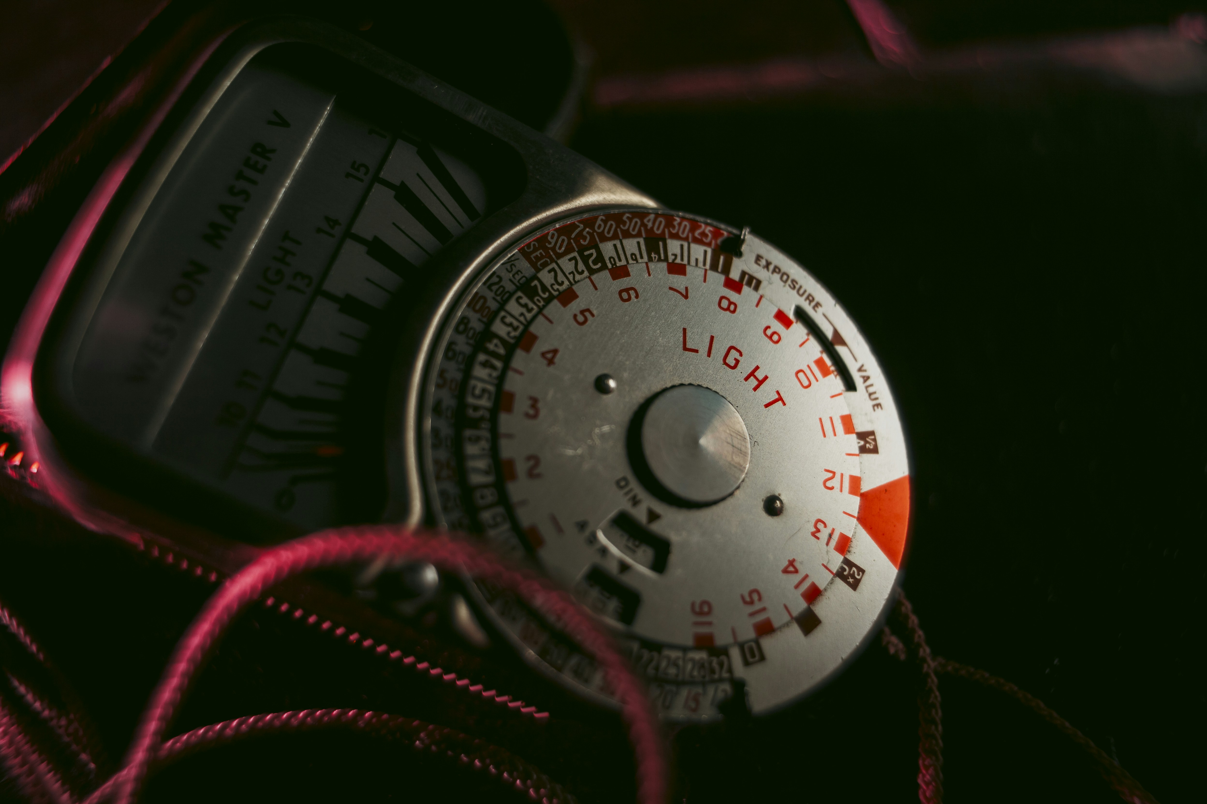 Crimson Knob: Close-Up of a Vintage Camera Dial Under Moody Light