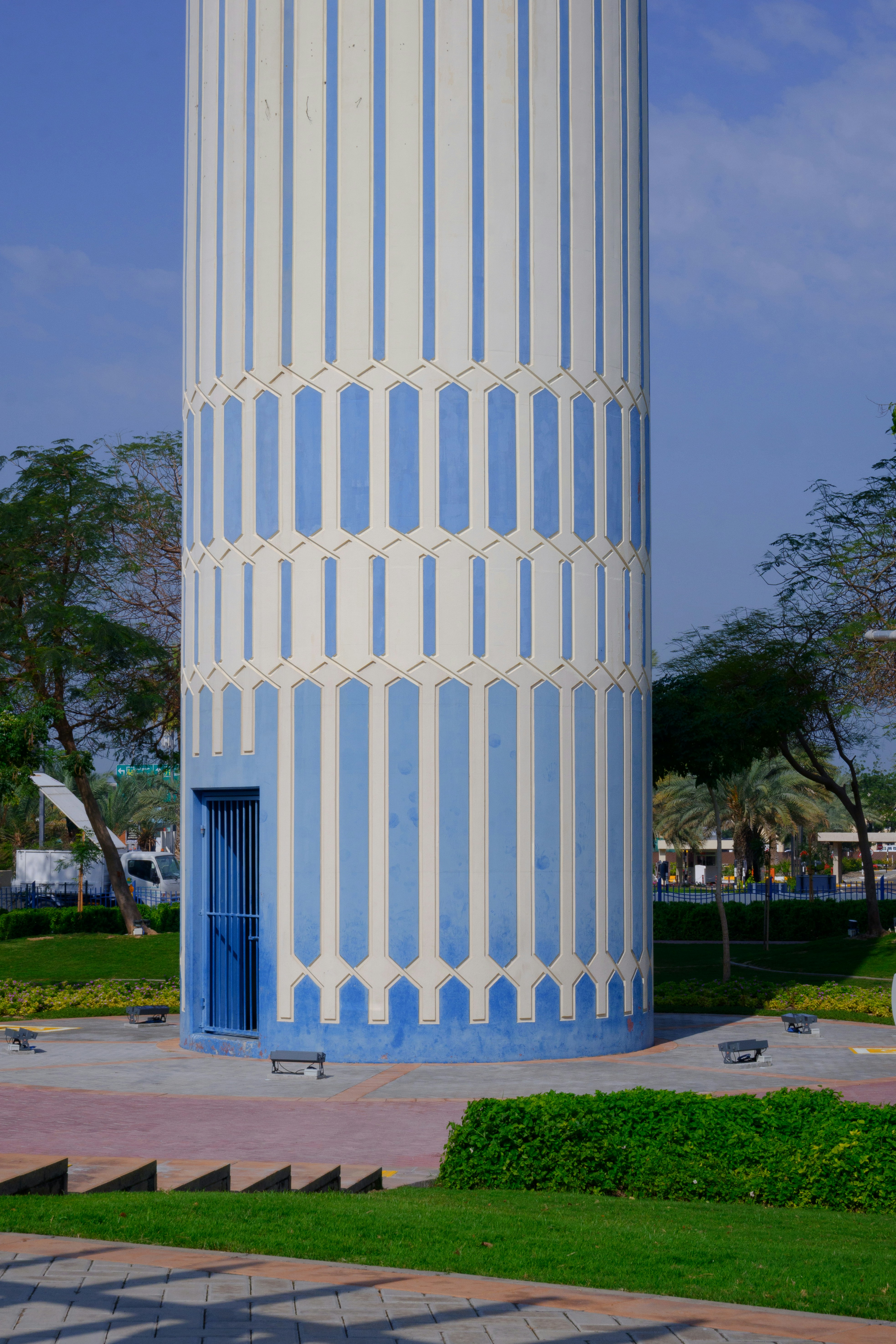Cobalt Cylinder with White Lattice Rises Over a Sunlit Park