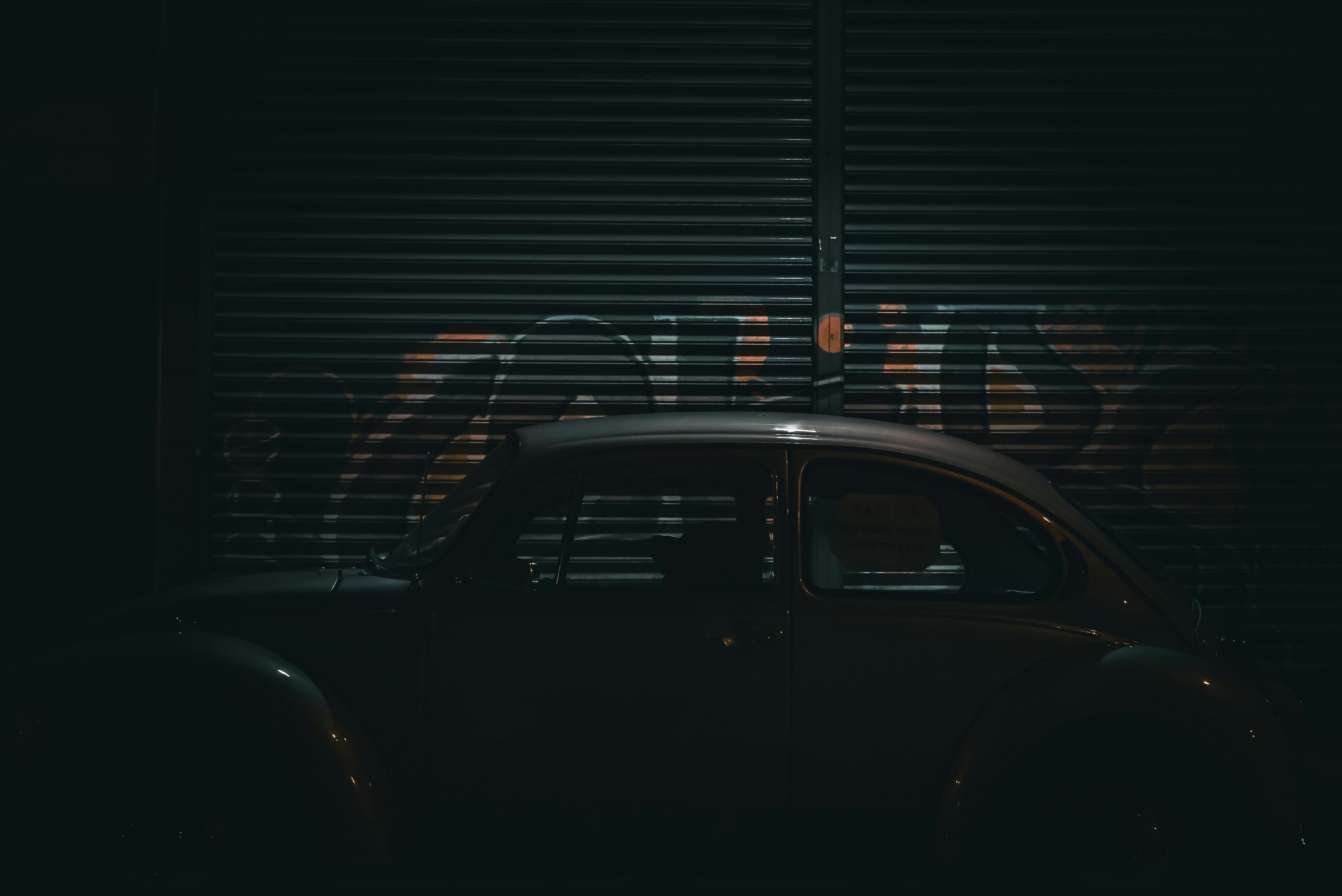 Noir silhouette: a vintage coupe framed by a graffiti-streaked shutter
